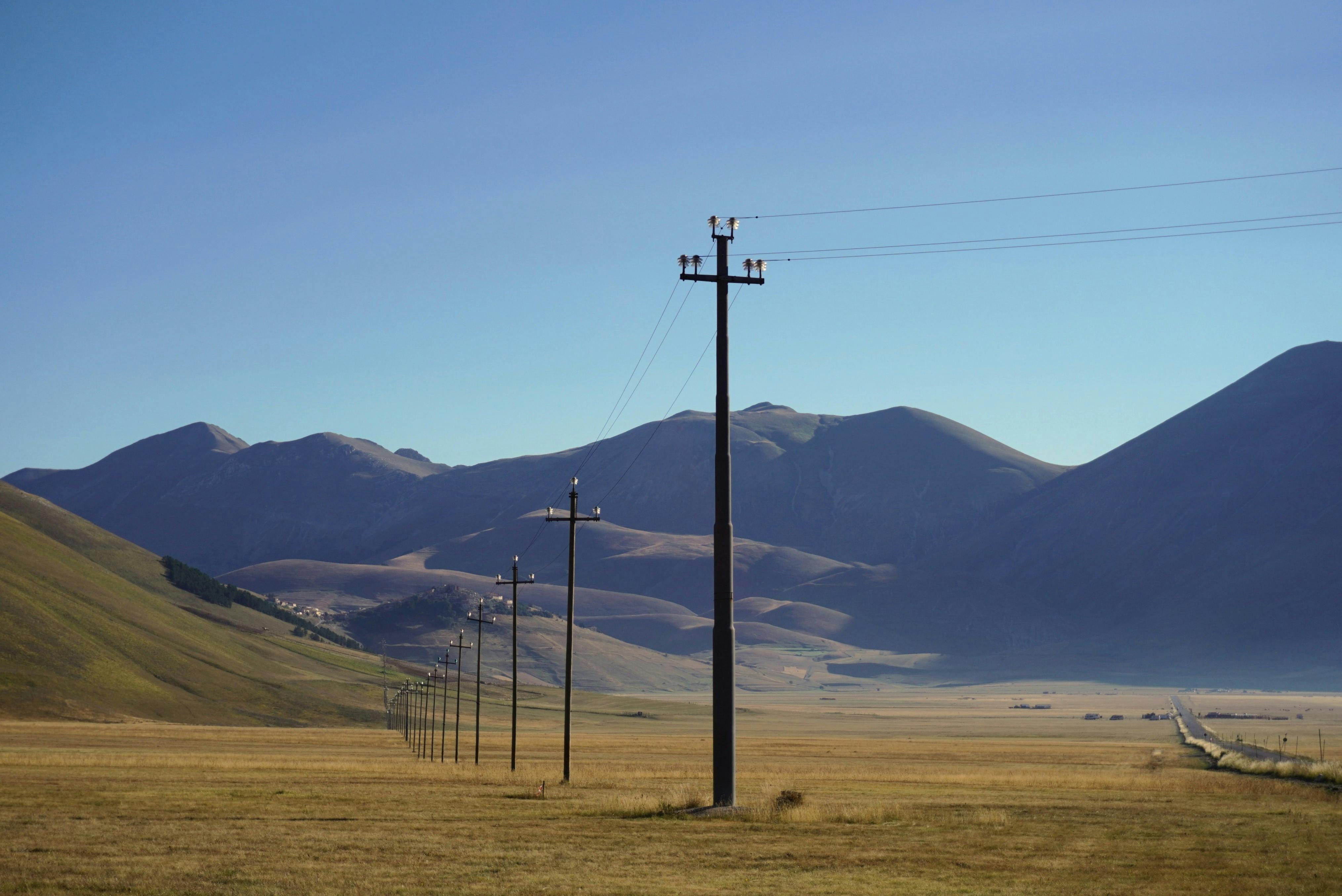 Long Row of Transmission Poles Across the Valley · Free Stock Photo