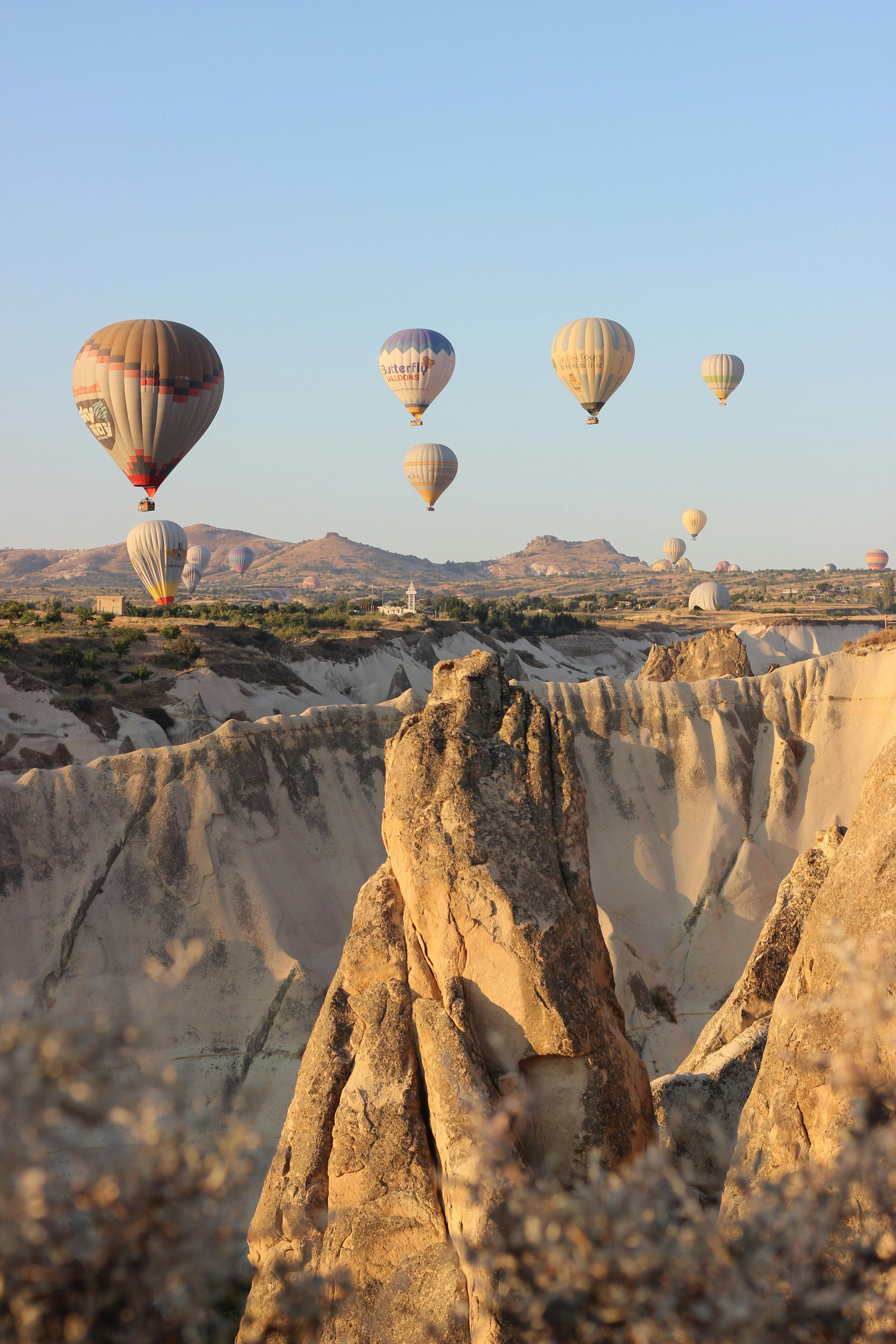 Flying Colorful Hot Air Balloons over Rock Formations · Free Stock Photo