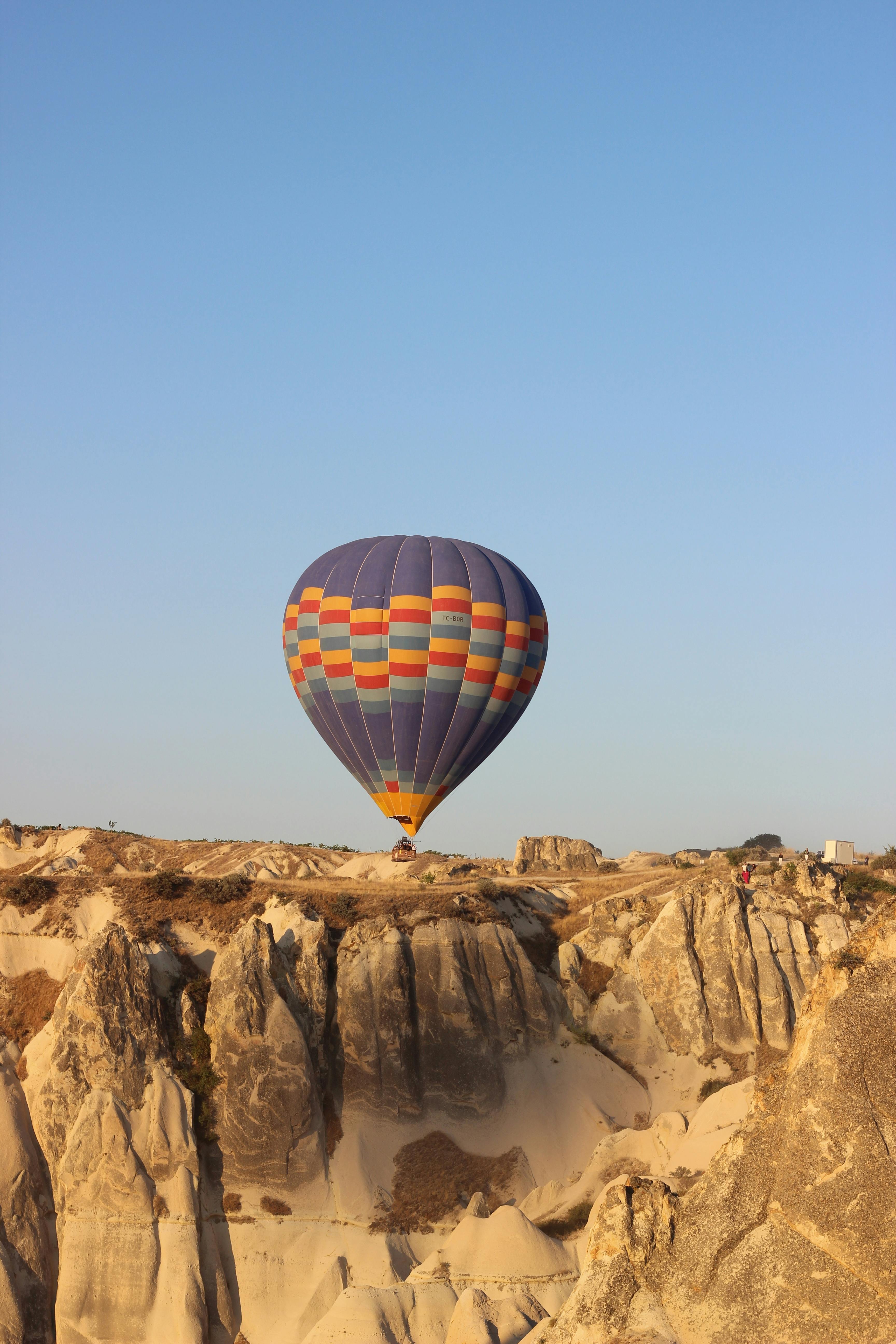 Colorful Hot Air Balloon Flying over Rock Formations · Free Stock Photo