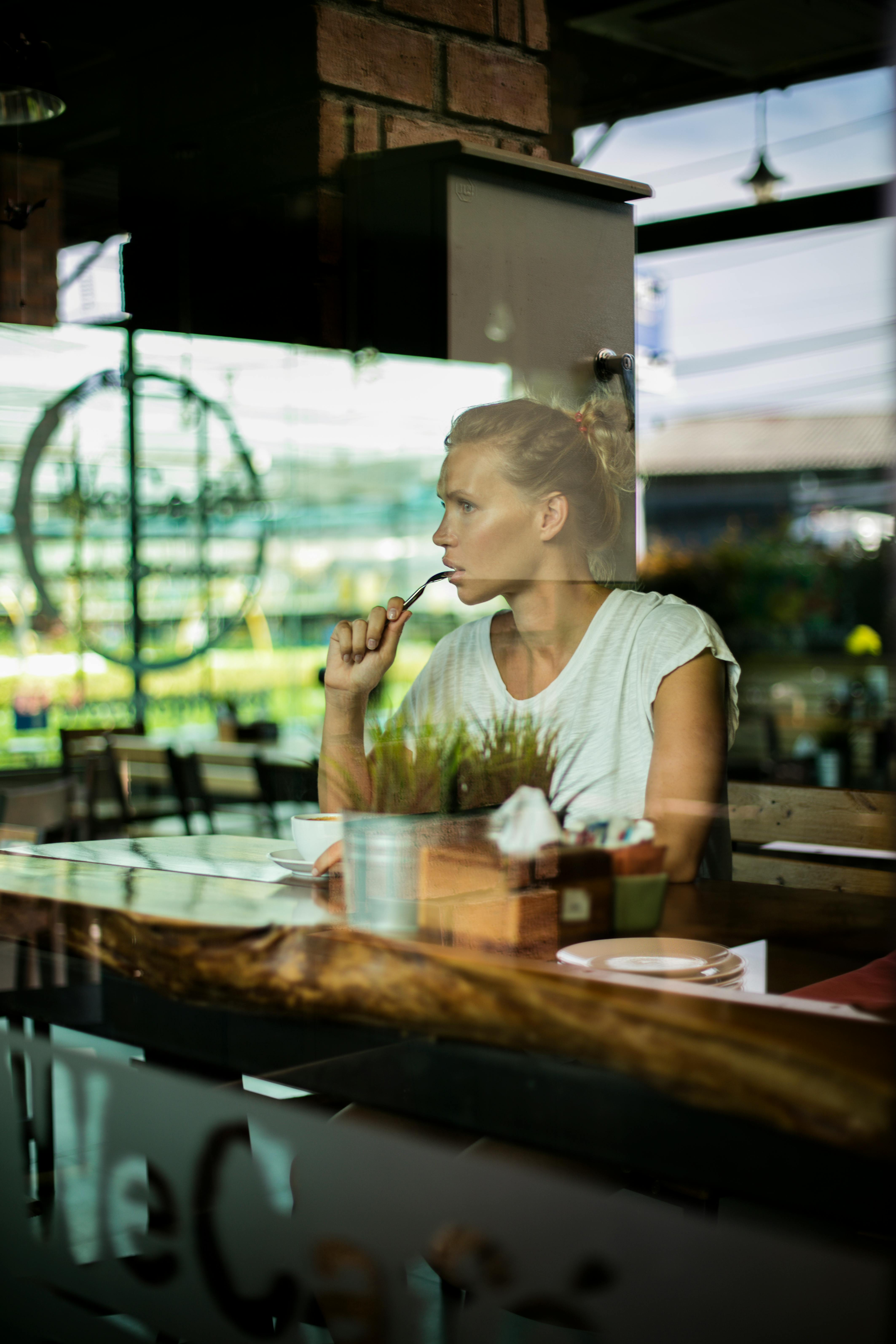 A Woman Biting a Spoon · Free Stock Photo