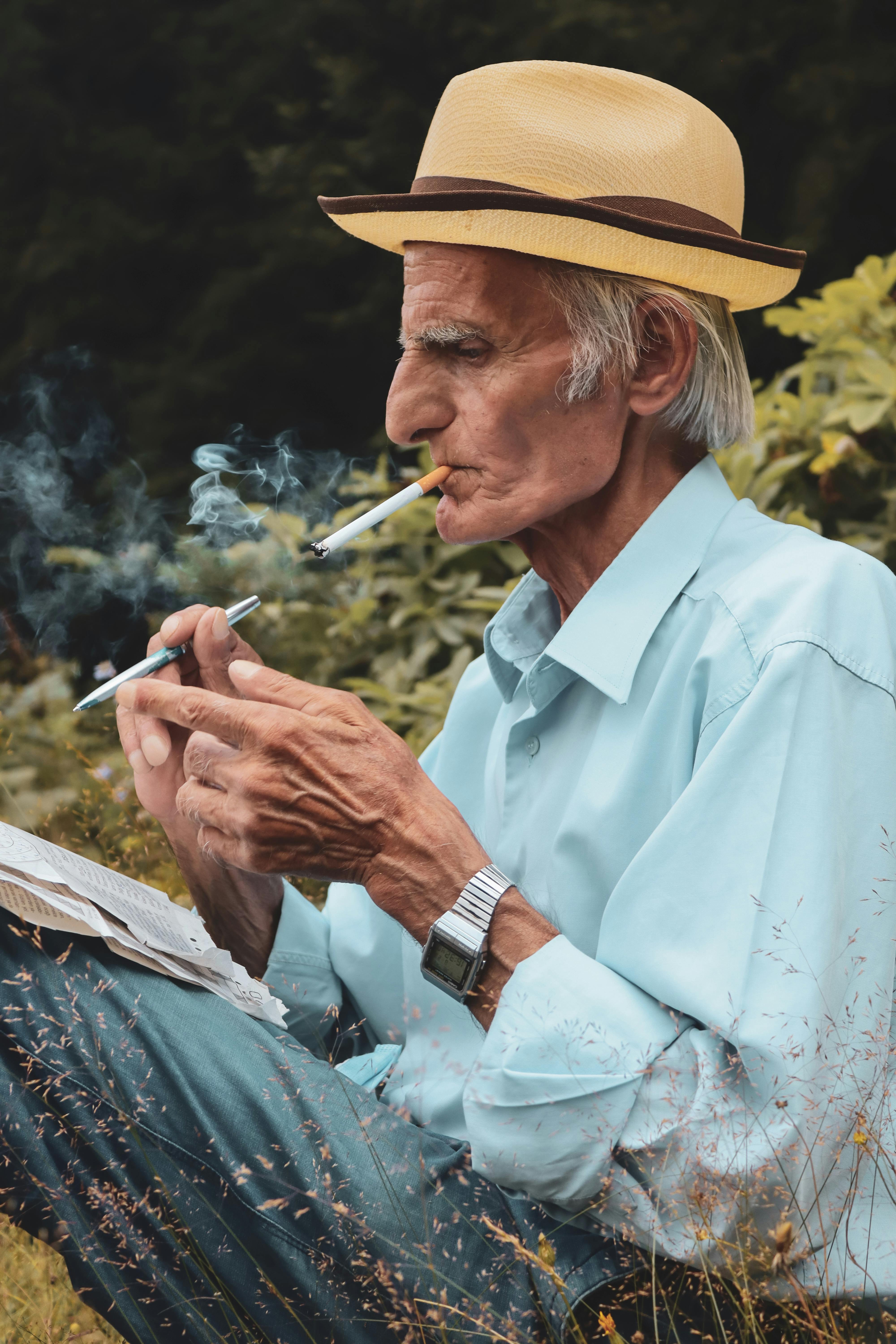 A Man Smoking a Cigarette while Leaning on a Truck · Free Stock Photo