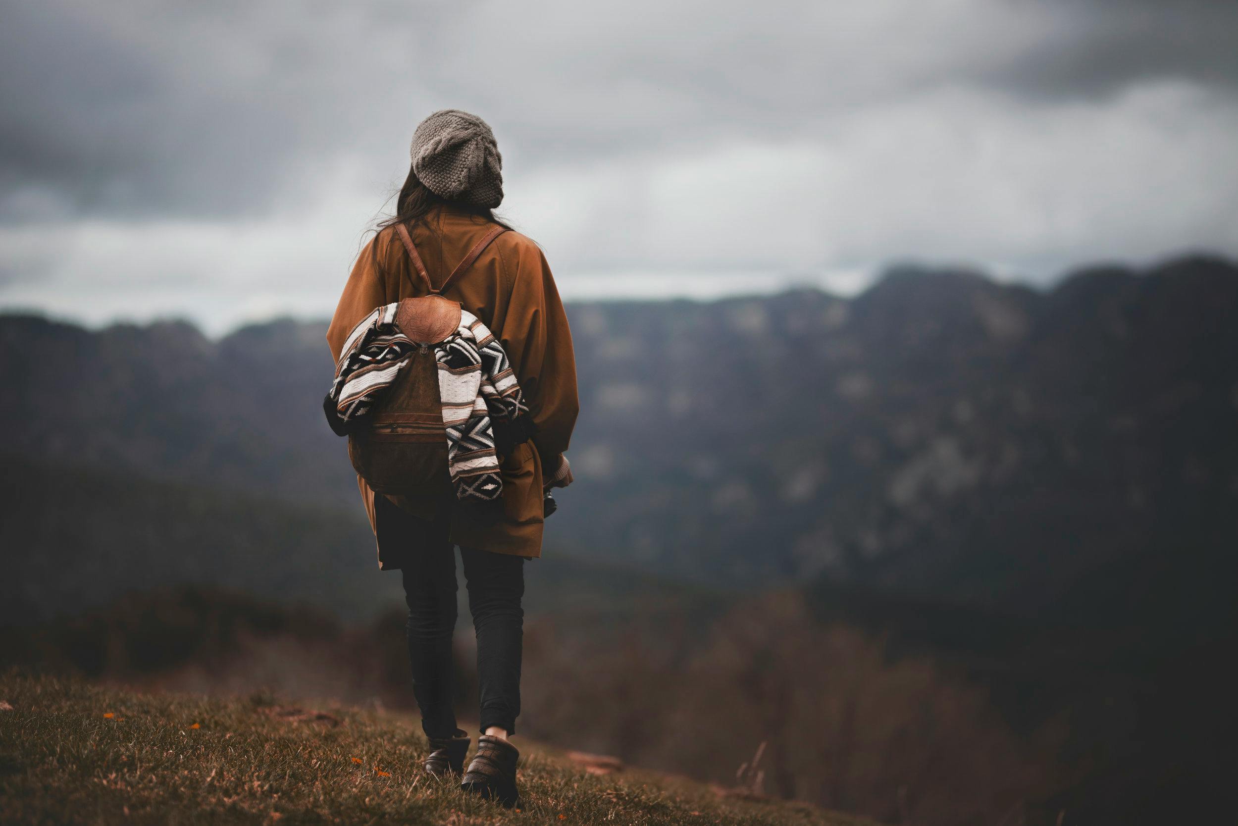 Back View of a Backpacker Walking on a Grass Field · Free Stock Photo