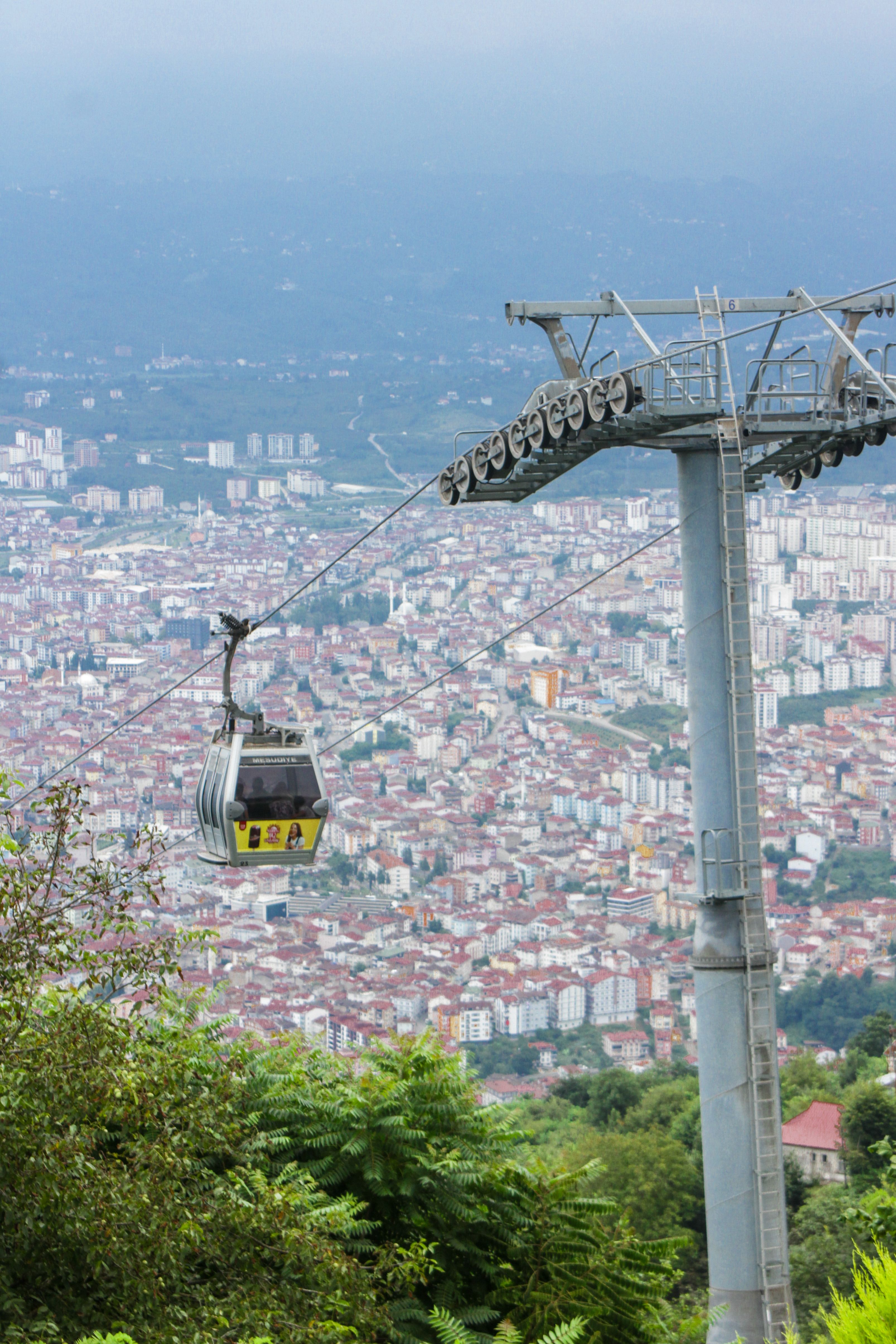 Cable Car Above Green Trees Over City Buildings · Free Stock Photo