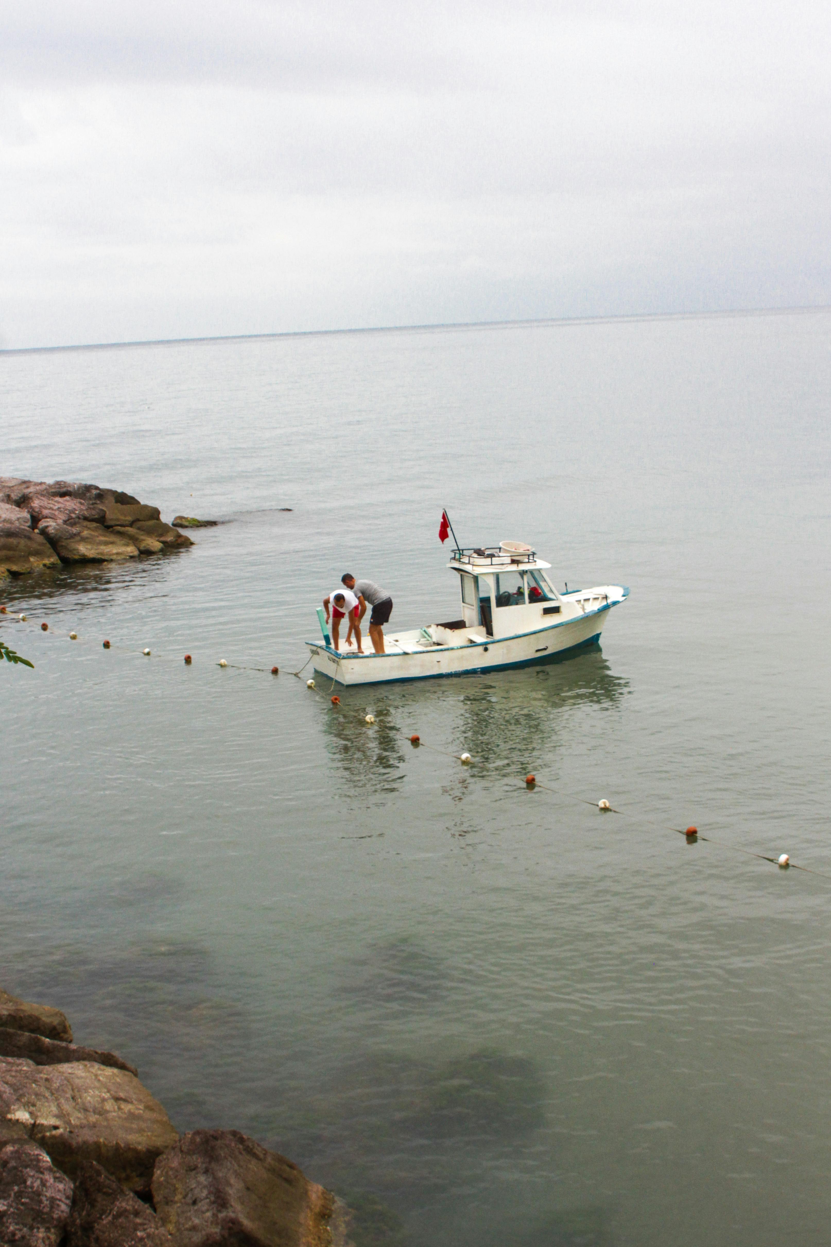 People on a White Boat Putting Floaters on the Sea · Free Stock Photo