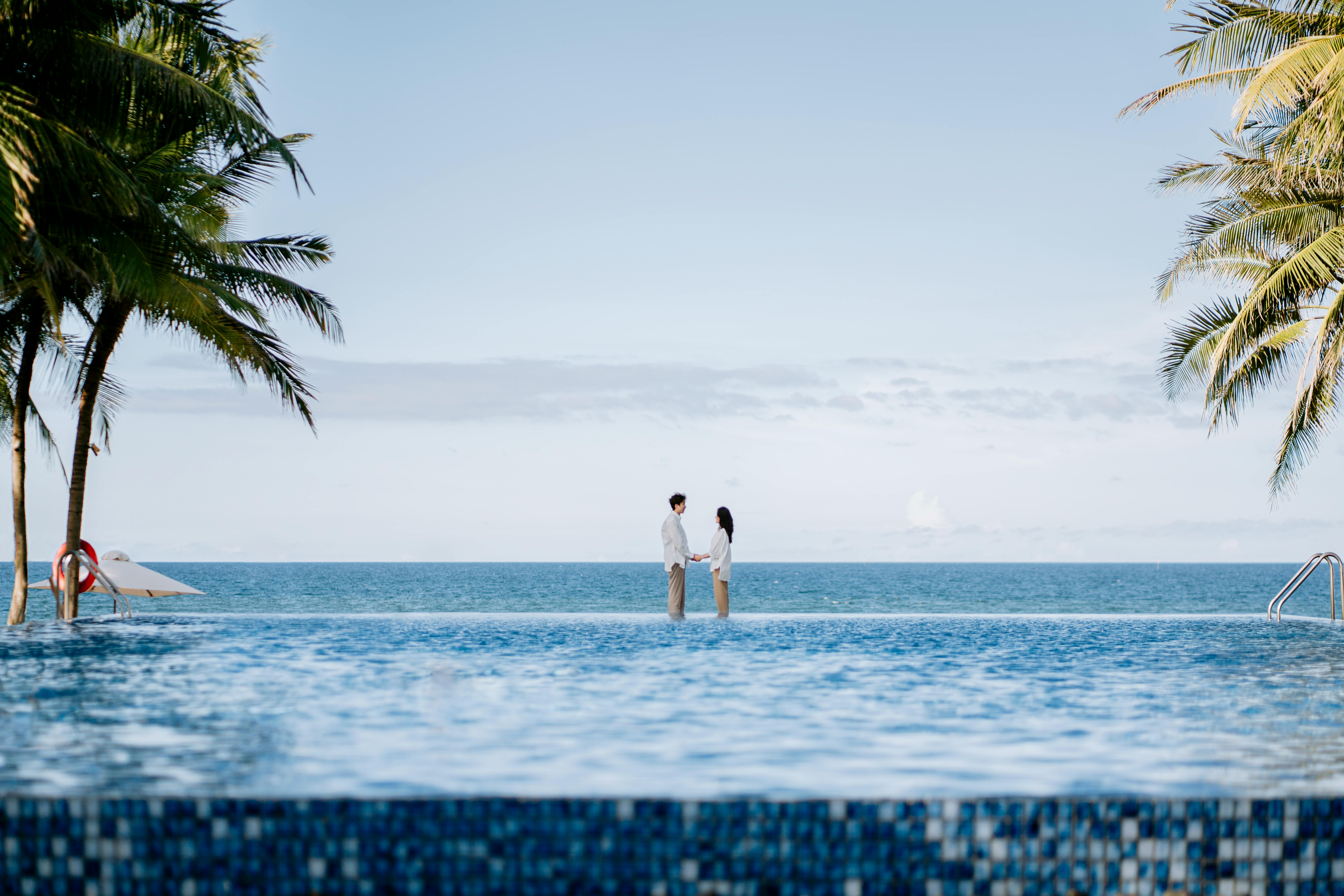Couple Standing between the Infinity Pool and the Ocean · Free Stock Photo