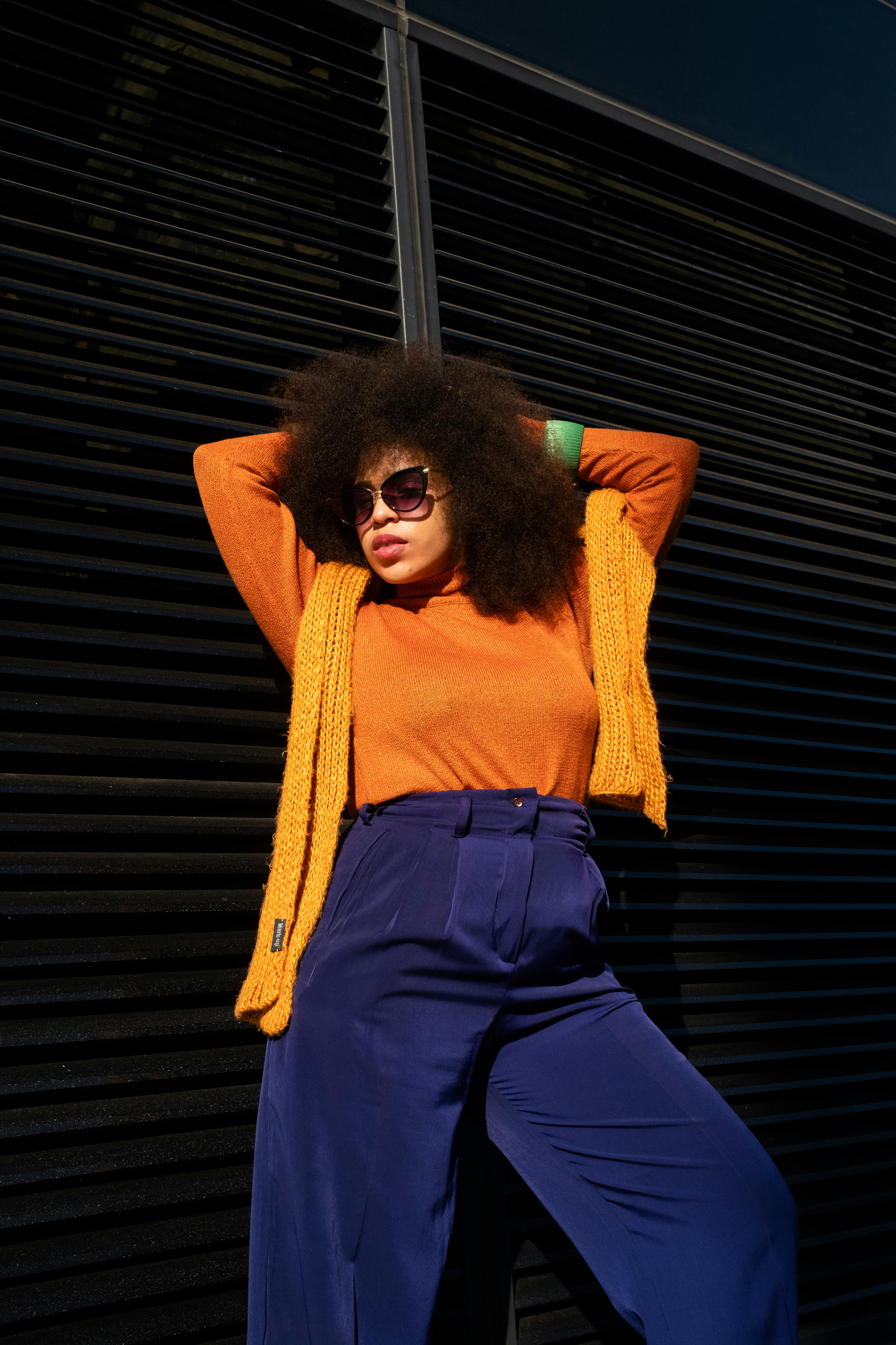 Woman with Afro Hairstyle Posing in Orange Blouse against Metal Wall ...