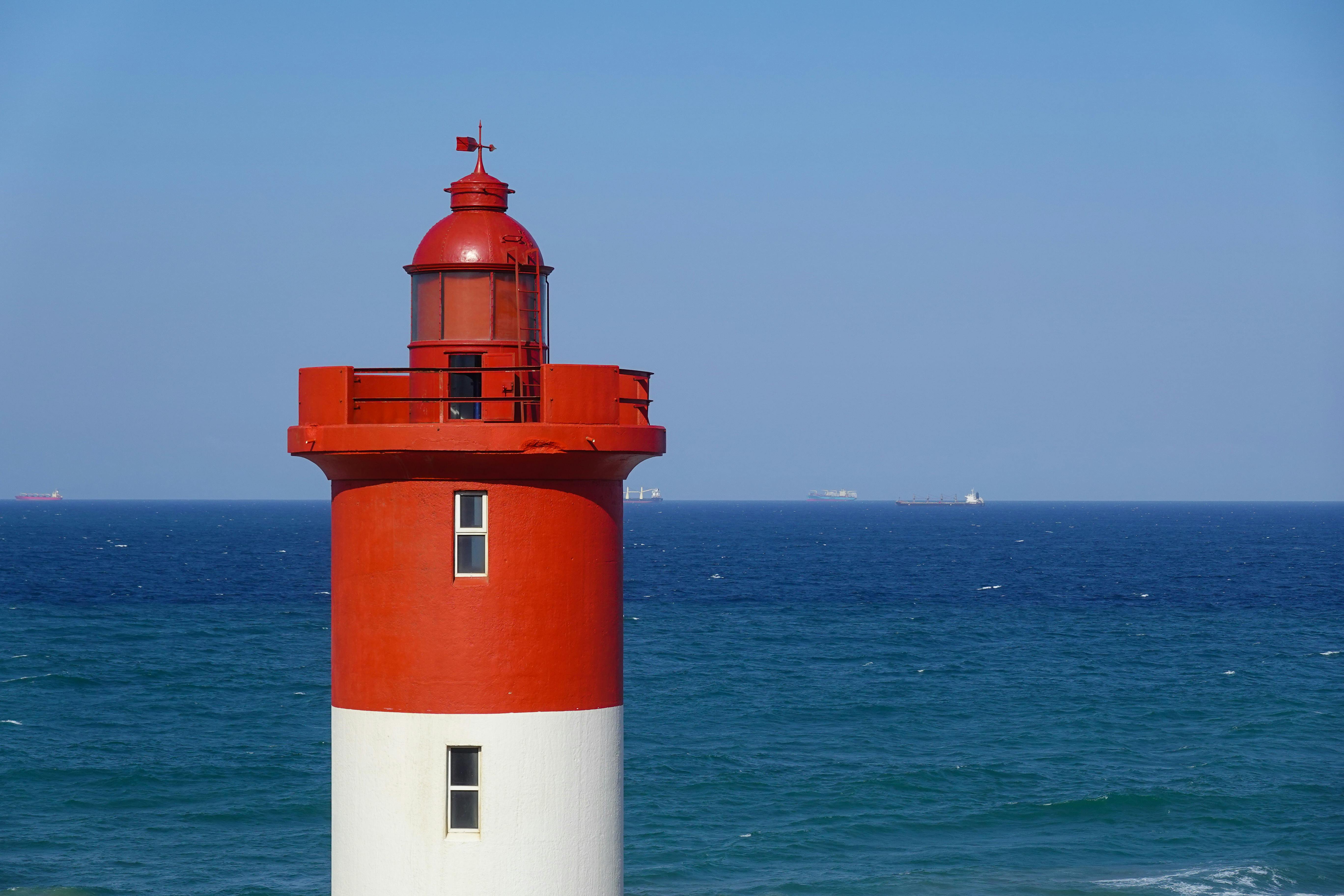 White and Red Lighthouse on Beach Shore · Free Stock Photo
