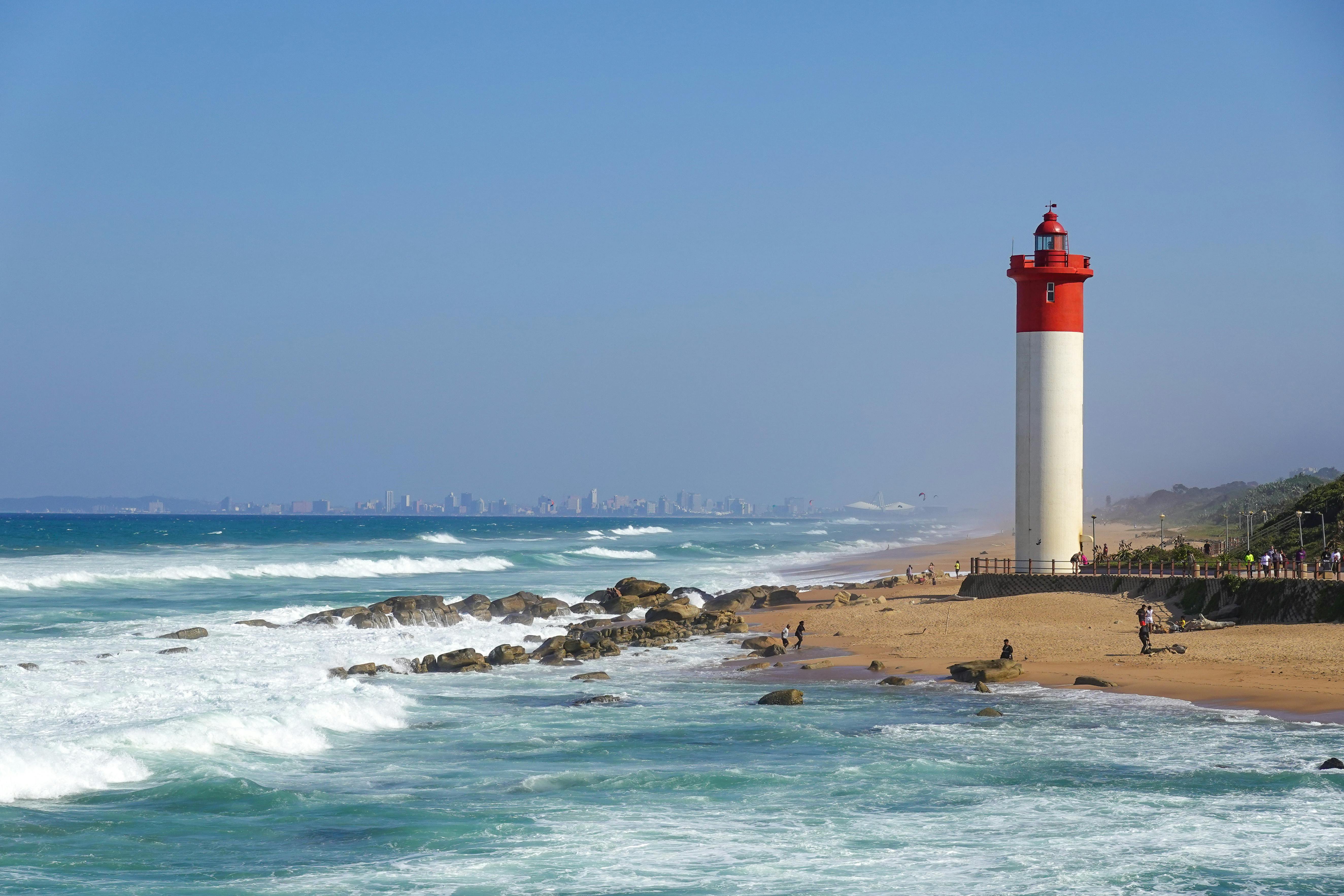 White and Red Lighthouse on Beach Shore · Free Stock Photo