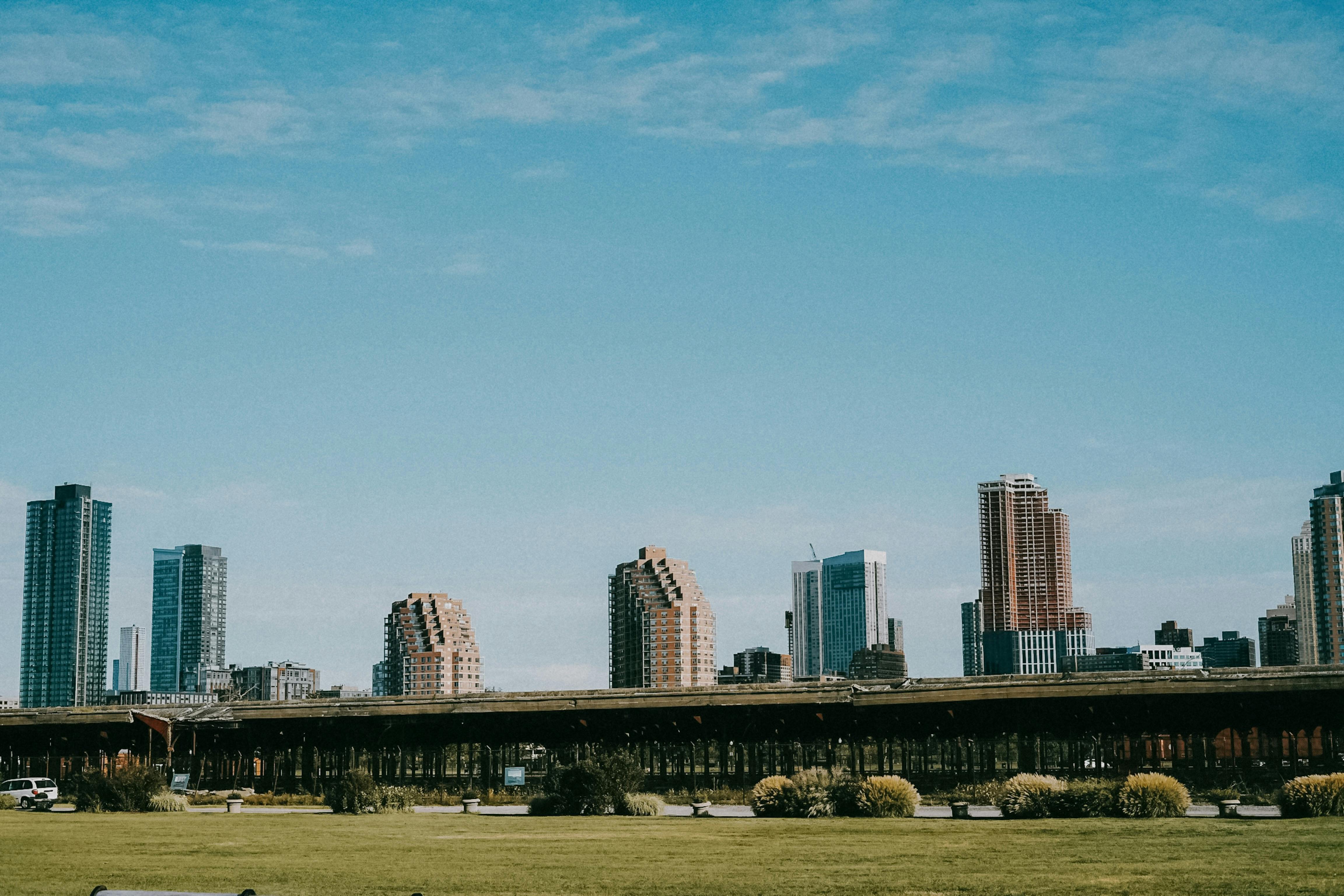 A Green Field with City View Under Blue Sky · Free Stock Photo