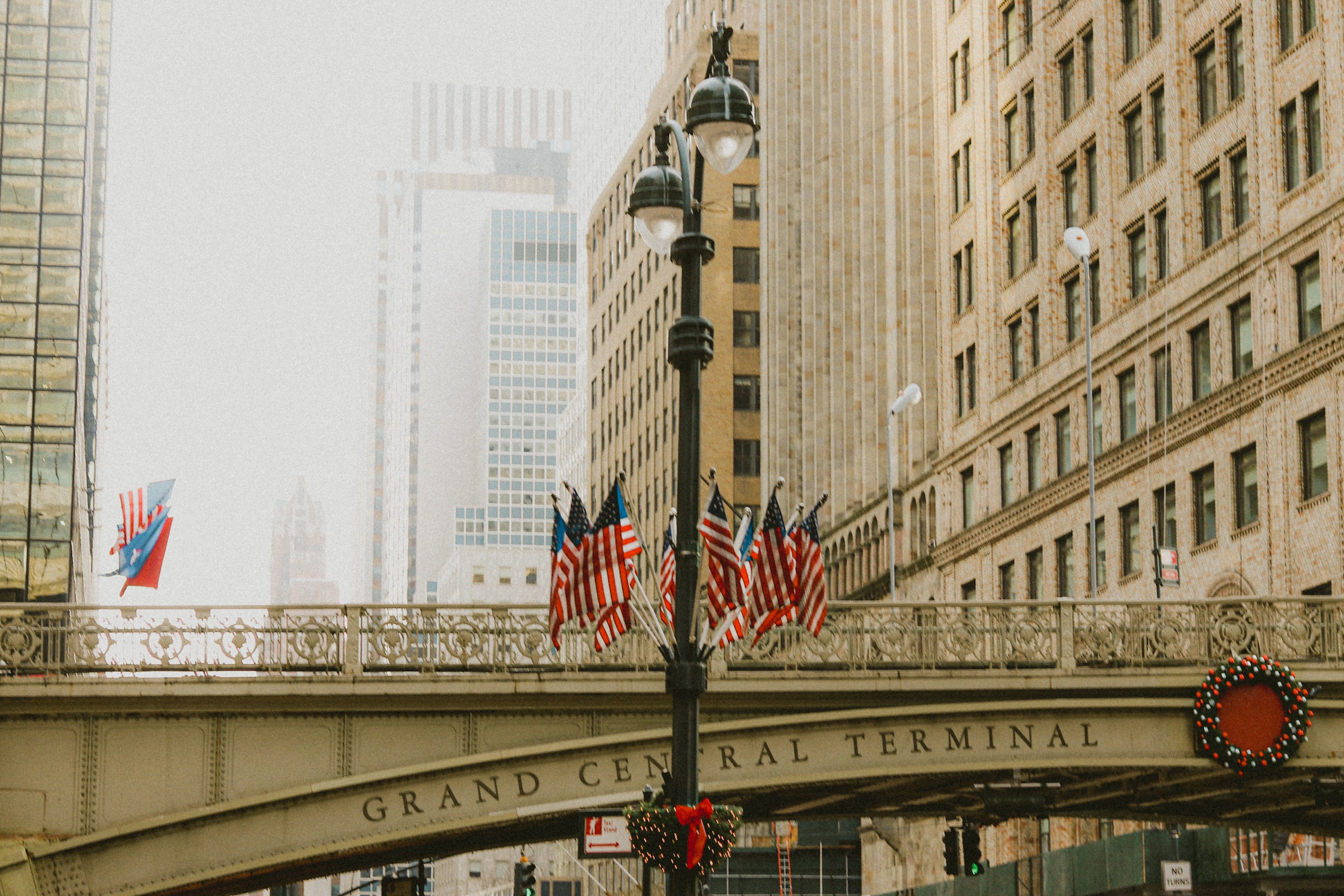 American Flags on a Lamp Post between Concrete Buildings · Free Stock Photo