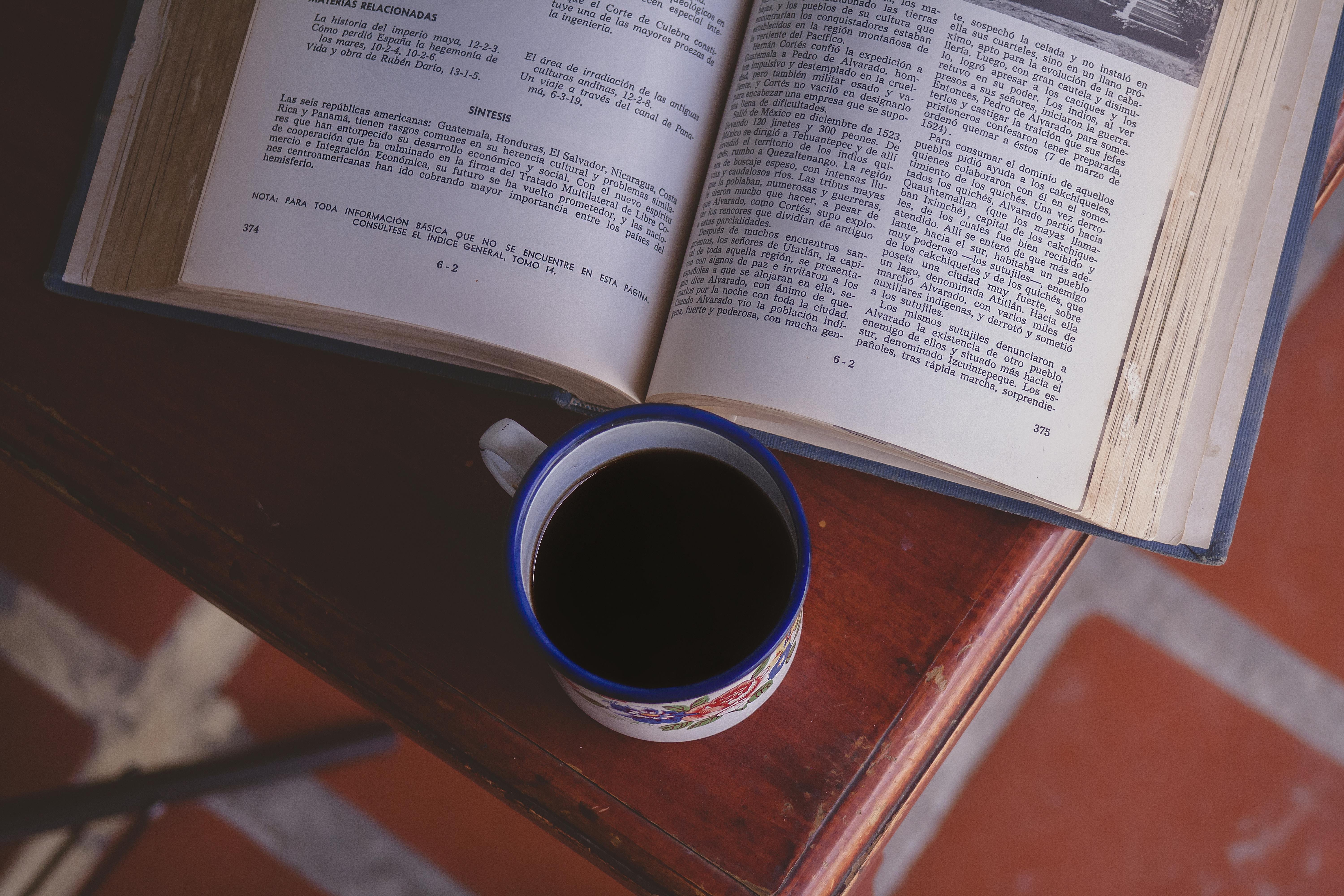 A Mug of Black Coffee Beside an Open Book on a Wooden Surface · Free ...