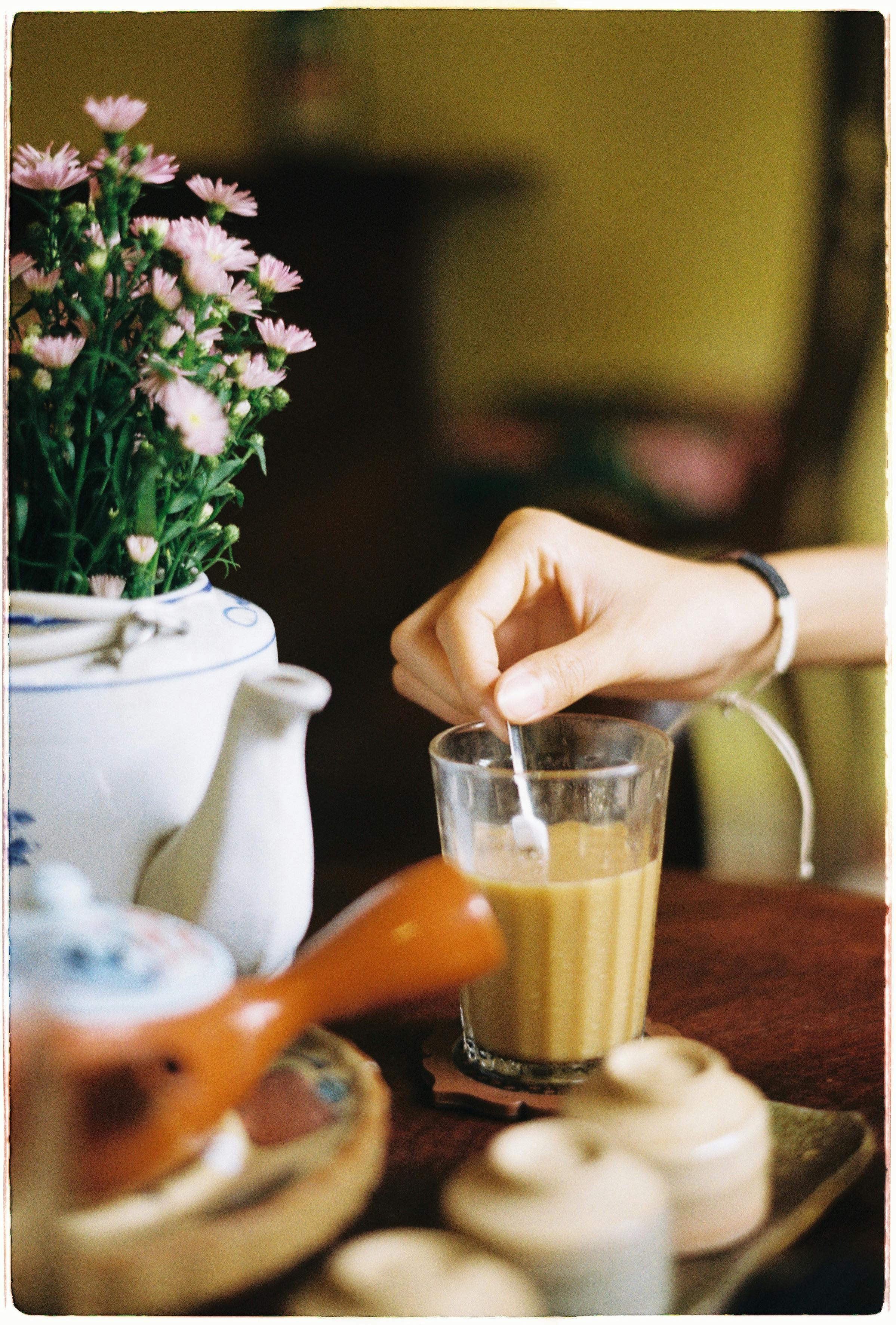 Hand of a Person Stirring Brown Liquid in a Clear Glass · Free Stock Photo