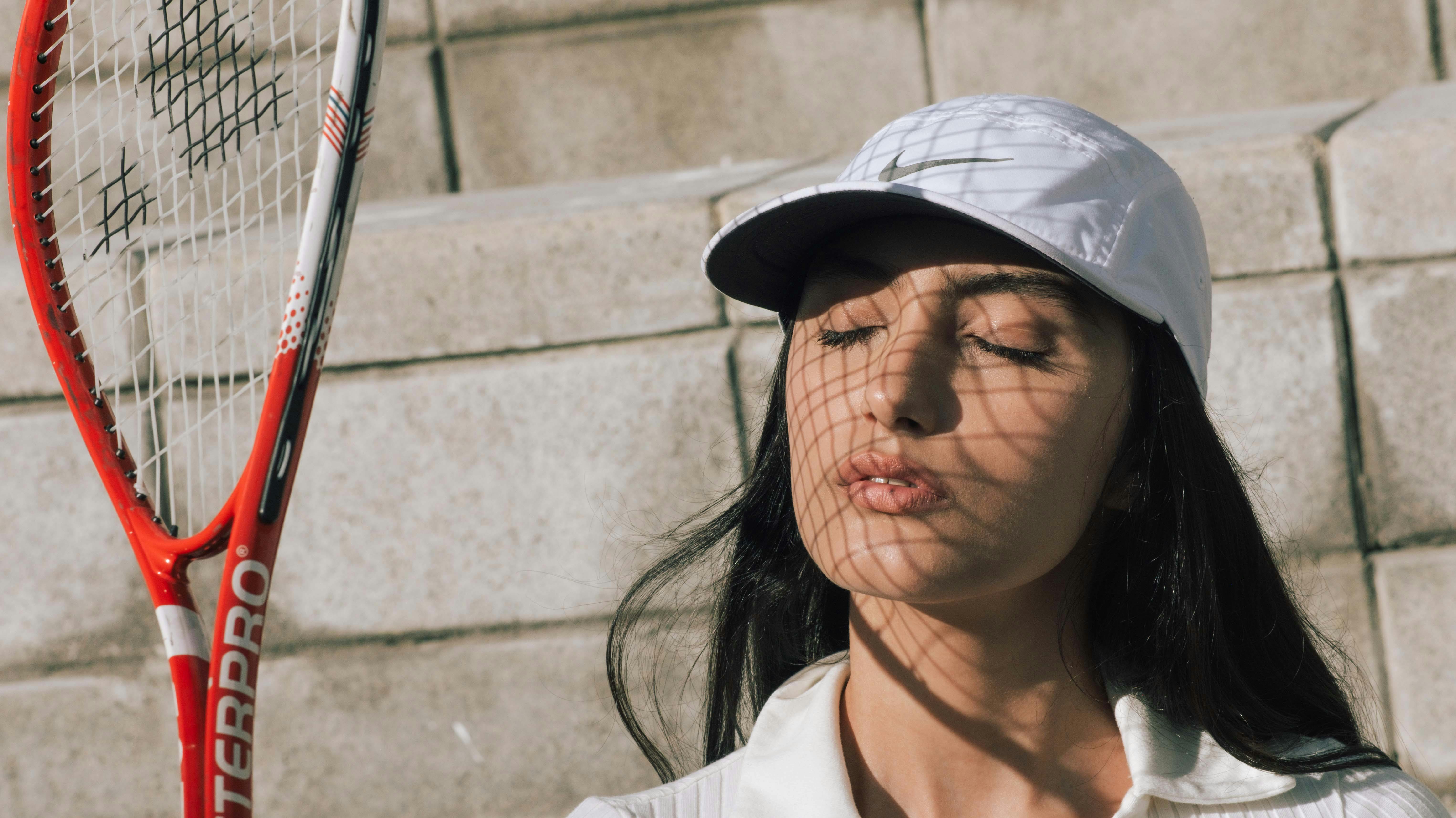 Brunette in Cap with Tennis Racket · Free Stock Photo