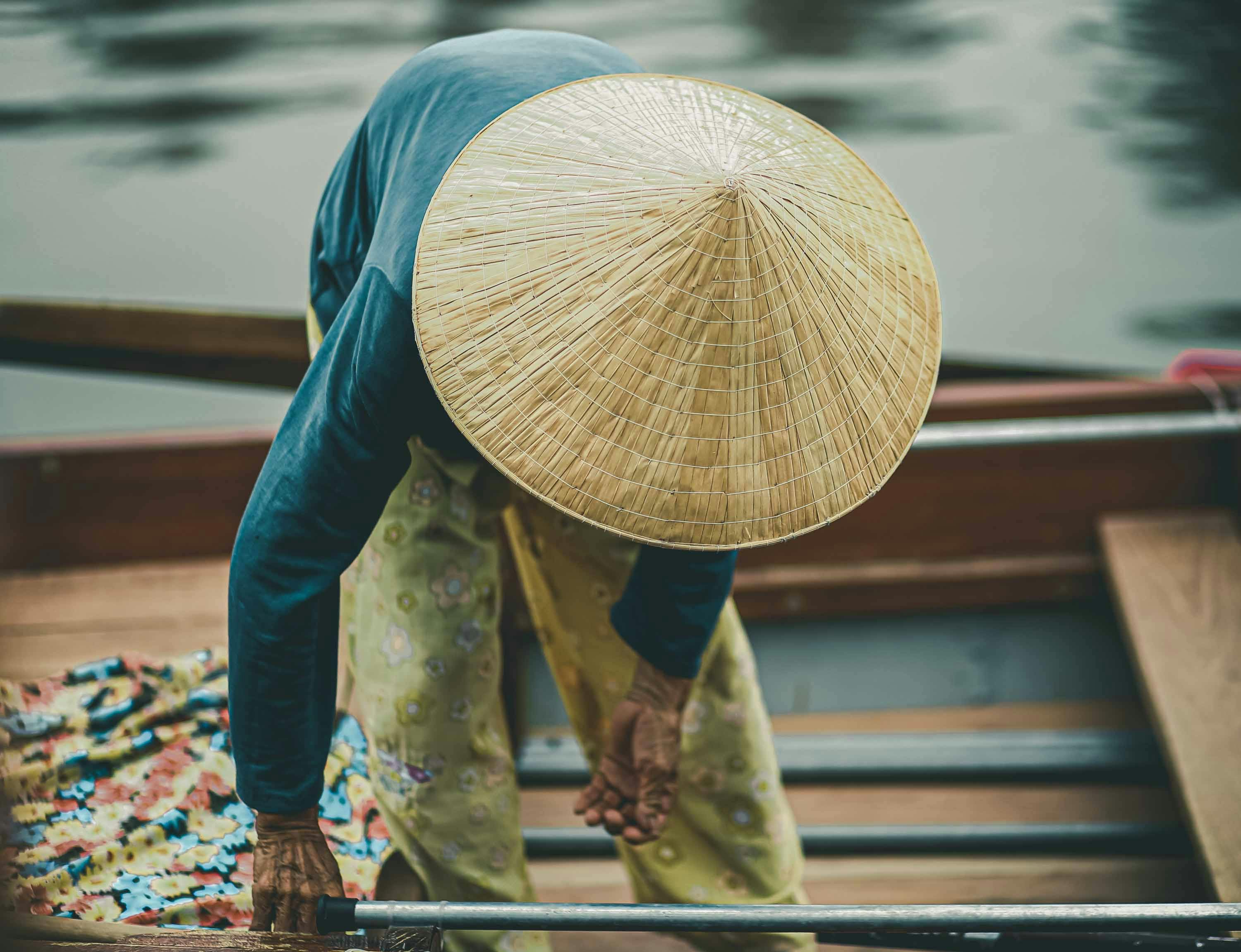 Person in Conical Hat Bending on Boat · Free Stock Photo