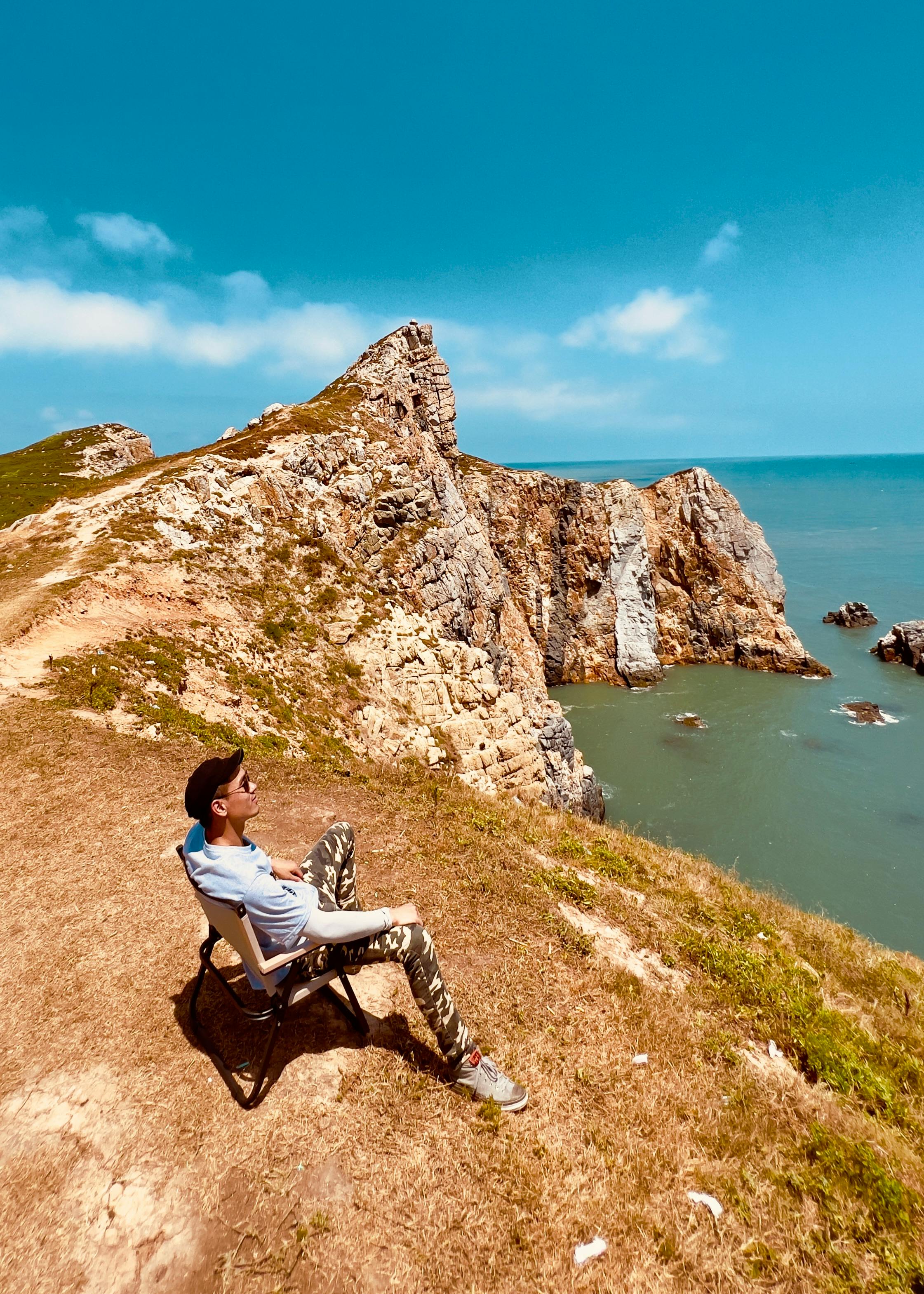 Man Sitting on Mountain Top Beside a Cliff · Free Stock Photo