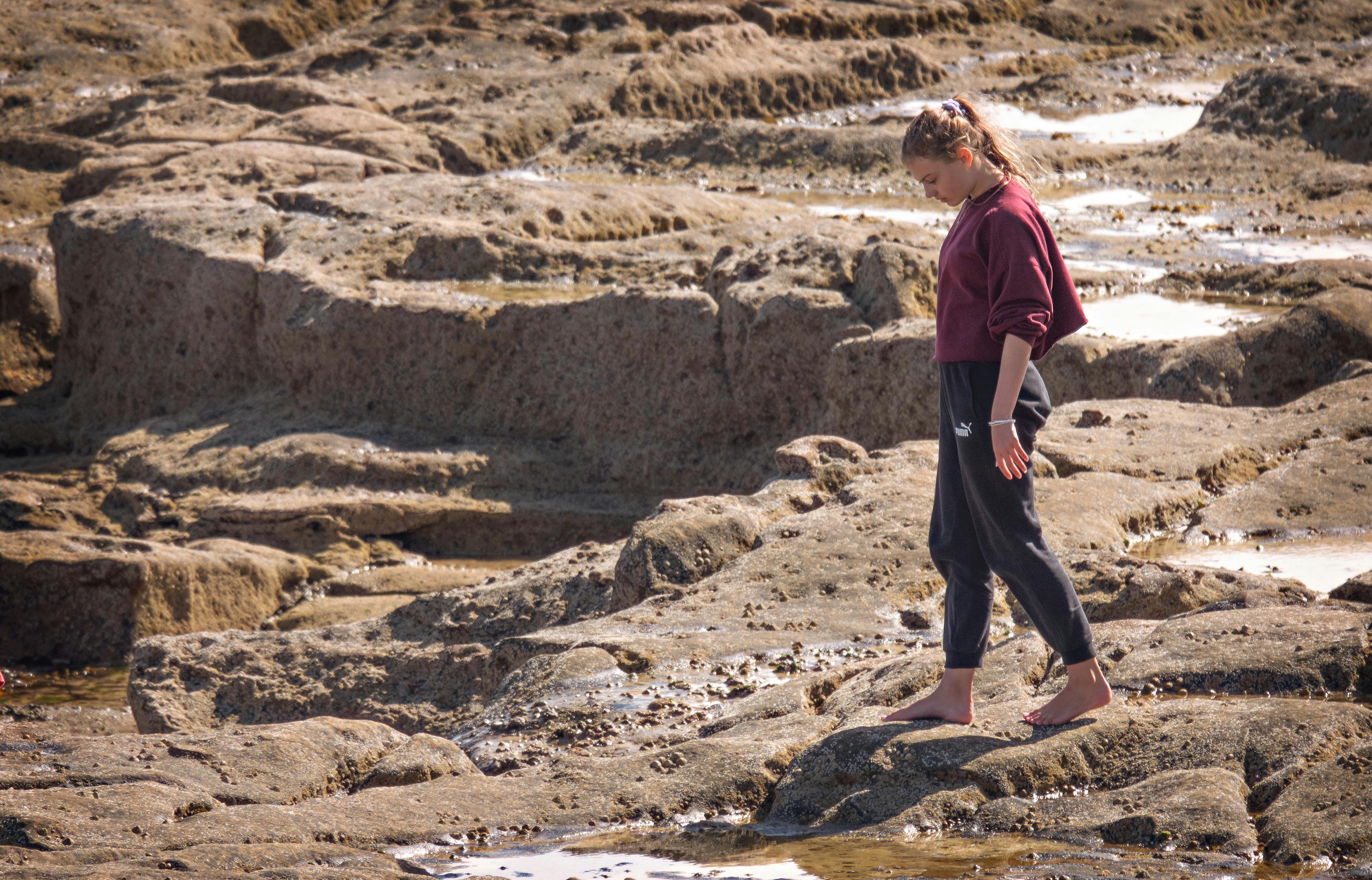 Young Woman Walking Barefoot on the Rocks near Water · Free Stock Photo