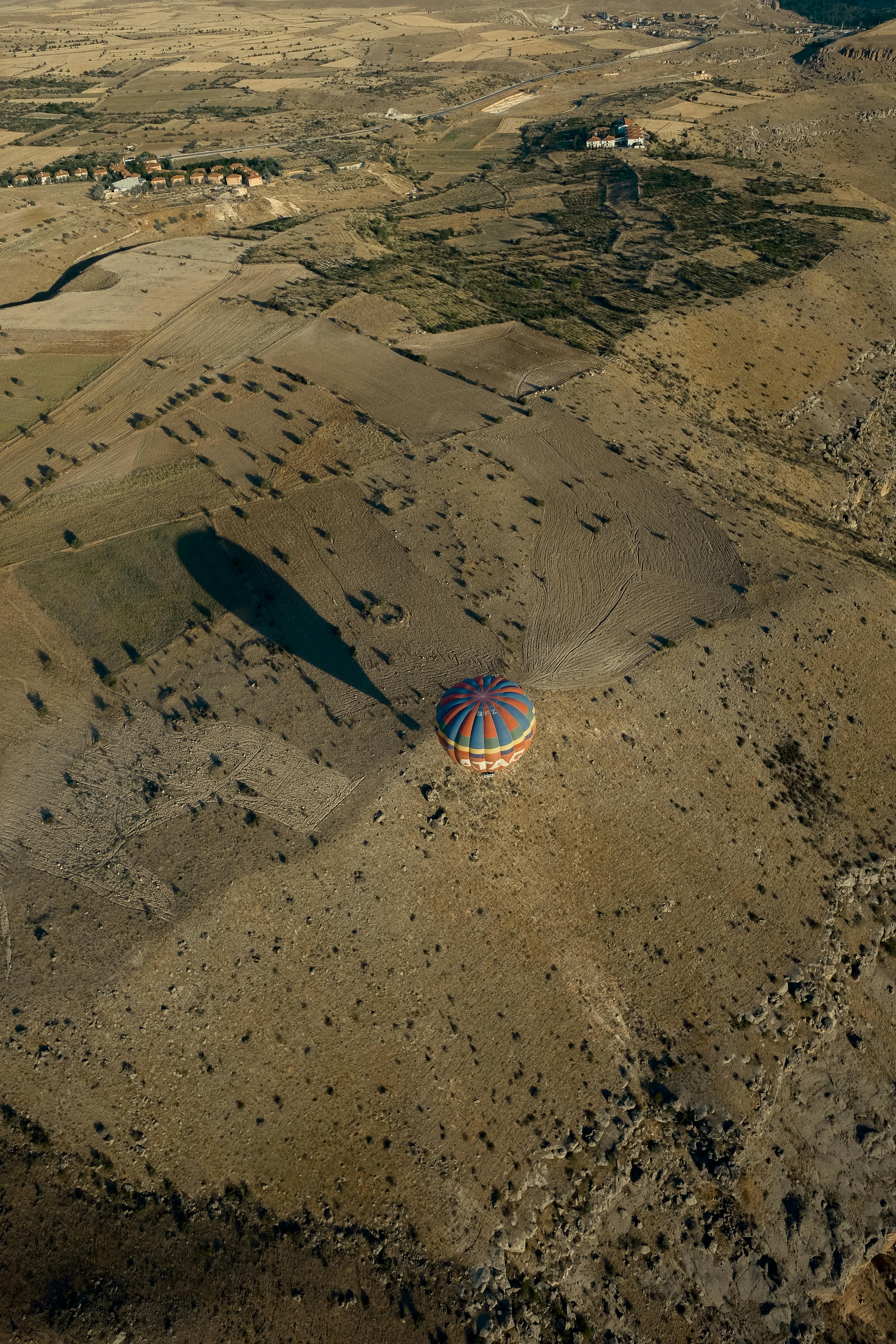 Aerial View of a Hot Air Balloon Flying over the Hills · Free Stock Photo