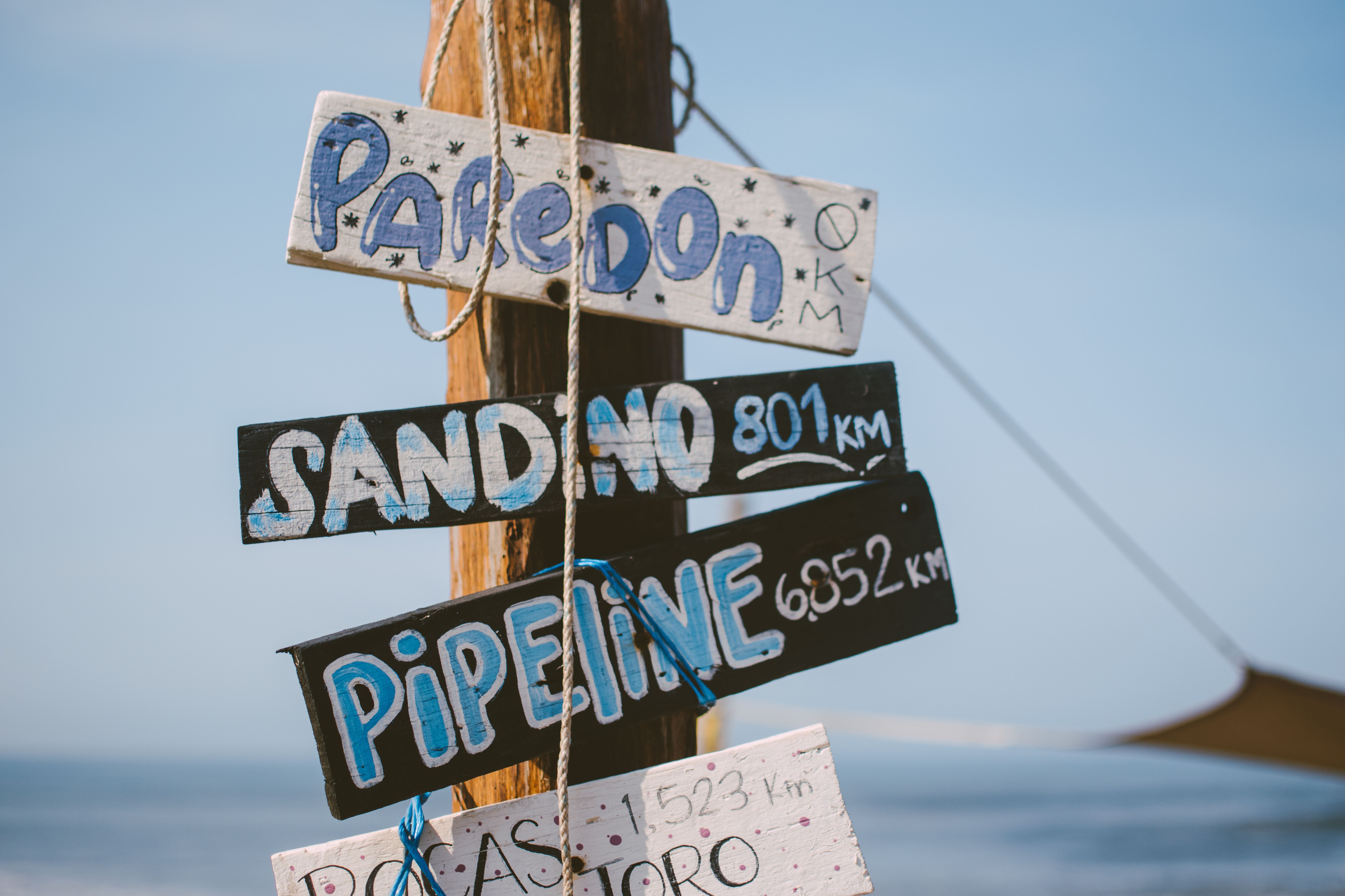 Brown Wooden Directional Sign Near Body of Water · Free Stock Photo