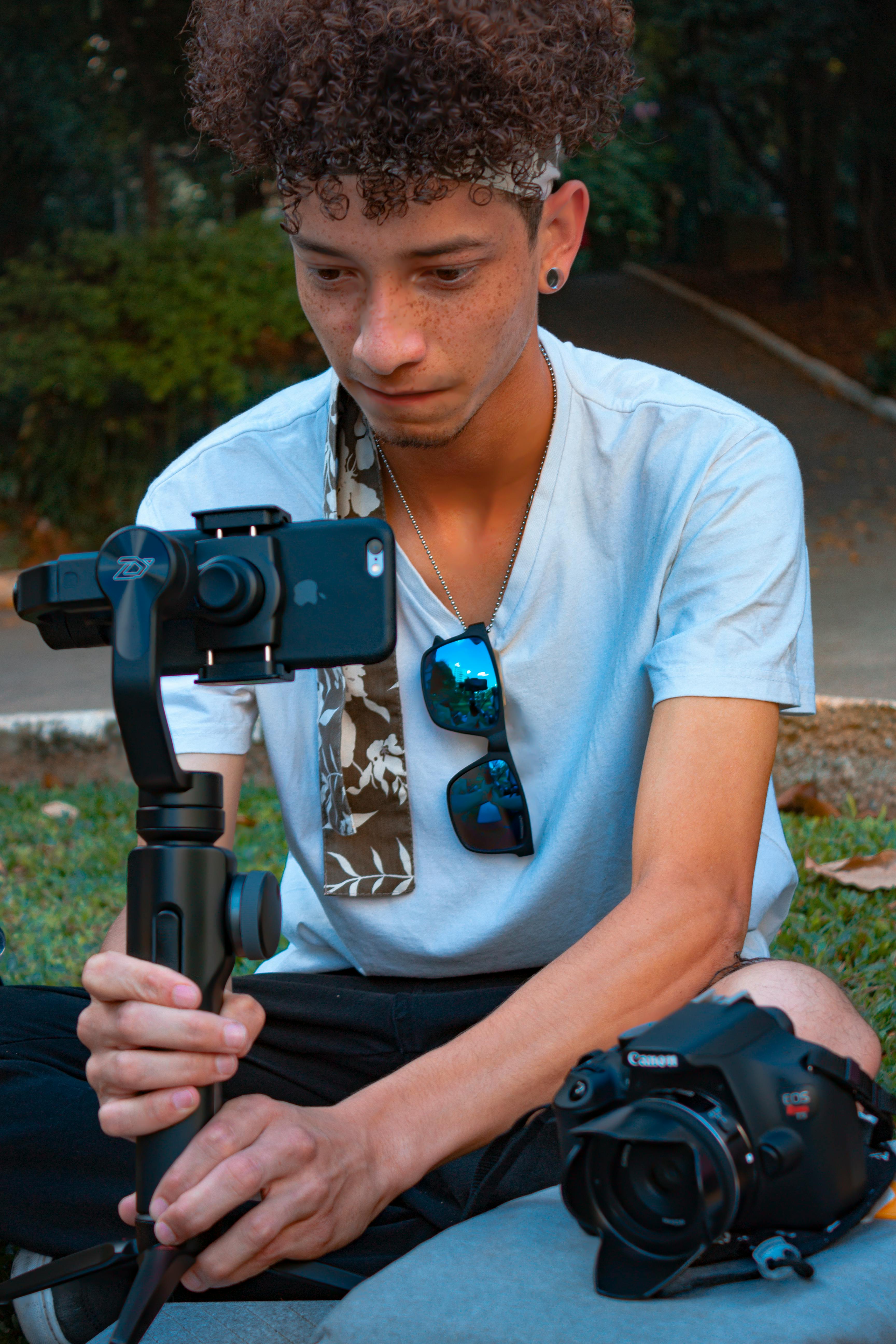 Man in White Crew Neck T-shirt Holding Black Dslr Camera · Free Stock Photo