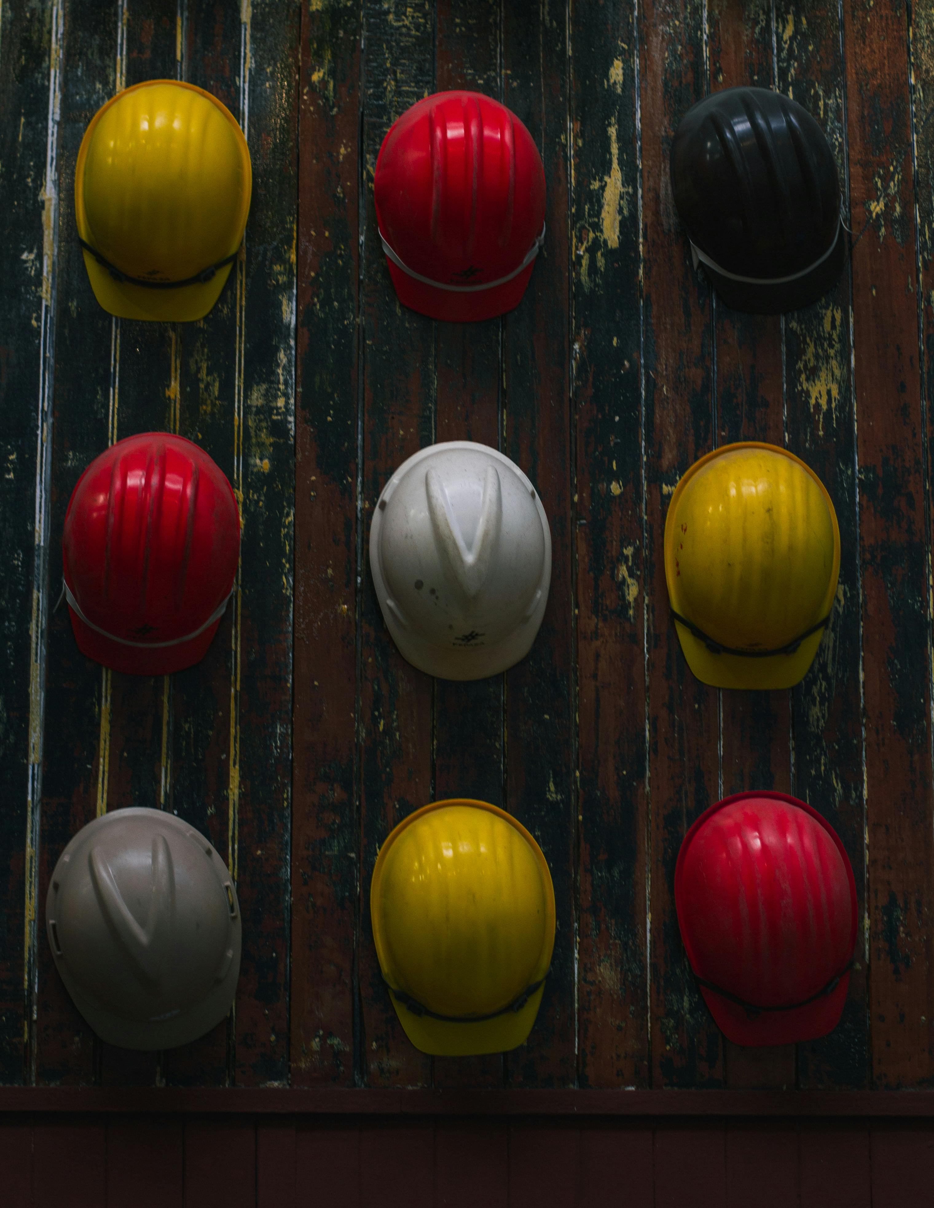 Red Yellow and White Hard Hats on Brown Wooden Surface · Free Stock Photo