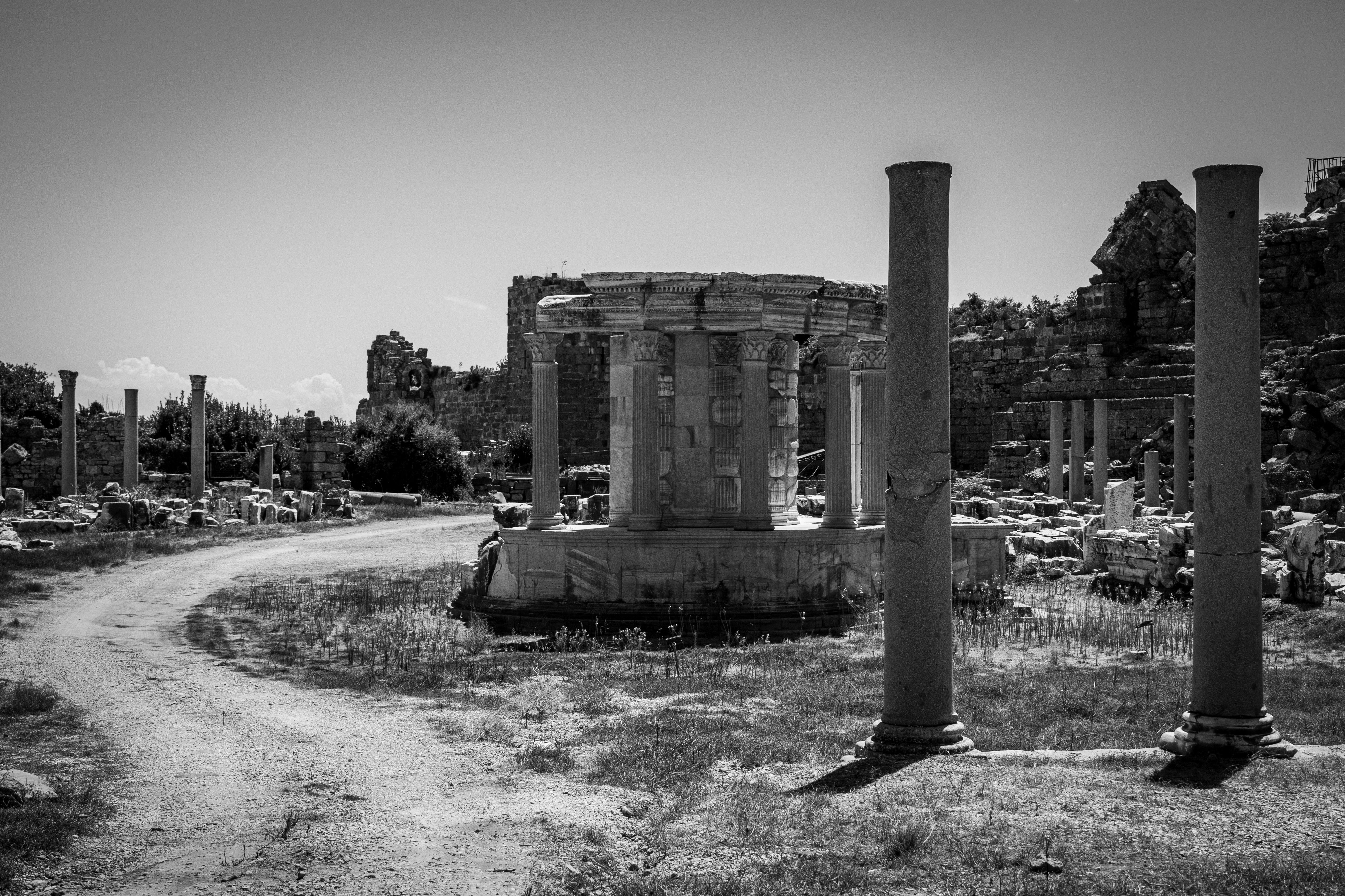 Black and White Photo of Ancient Ruins along Dirt Road · Free Stock Photo
