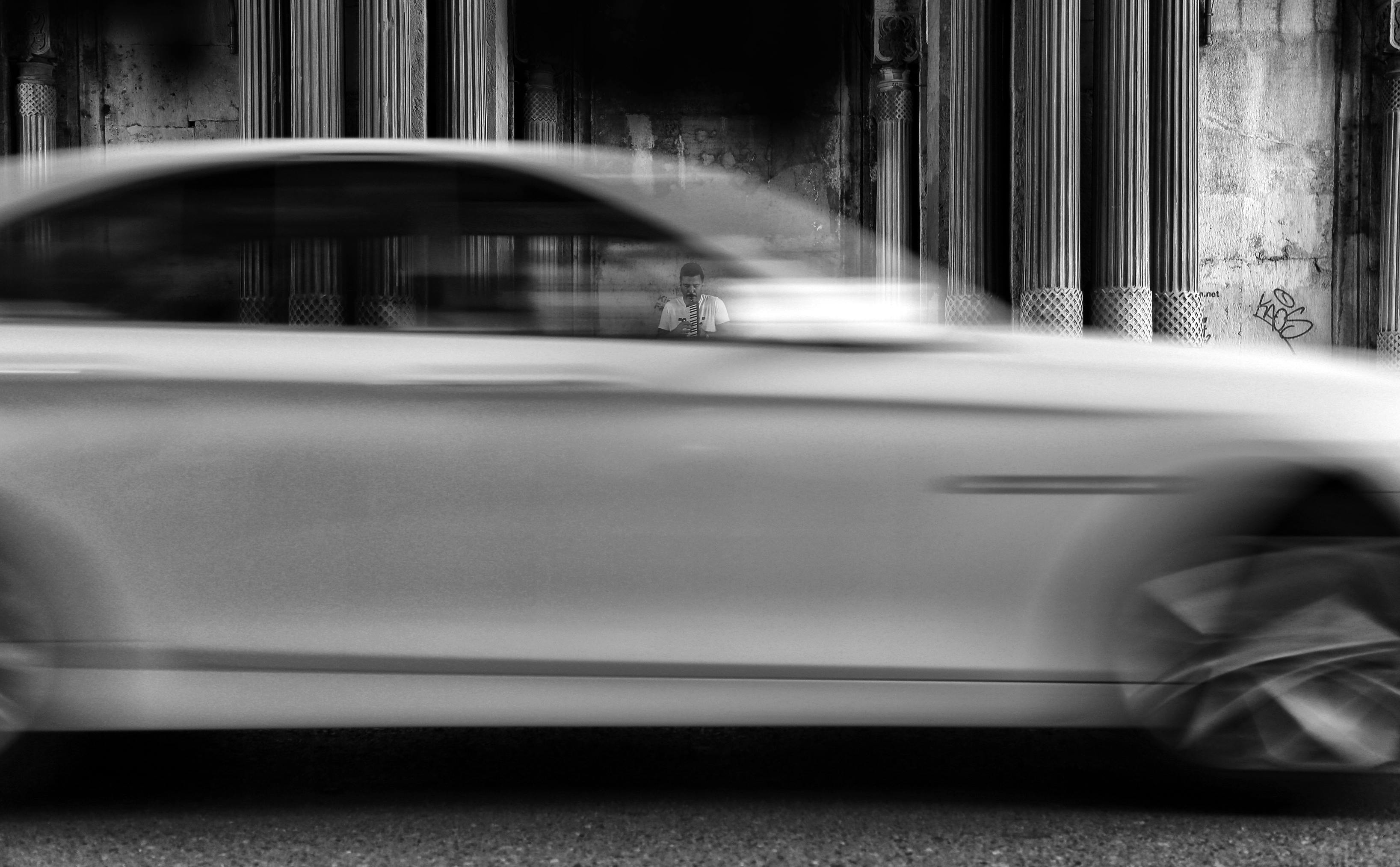A Grayscale Photo of a Moving Car on the Road · Free Stock Photo