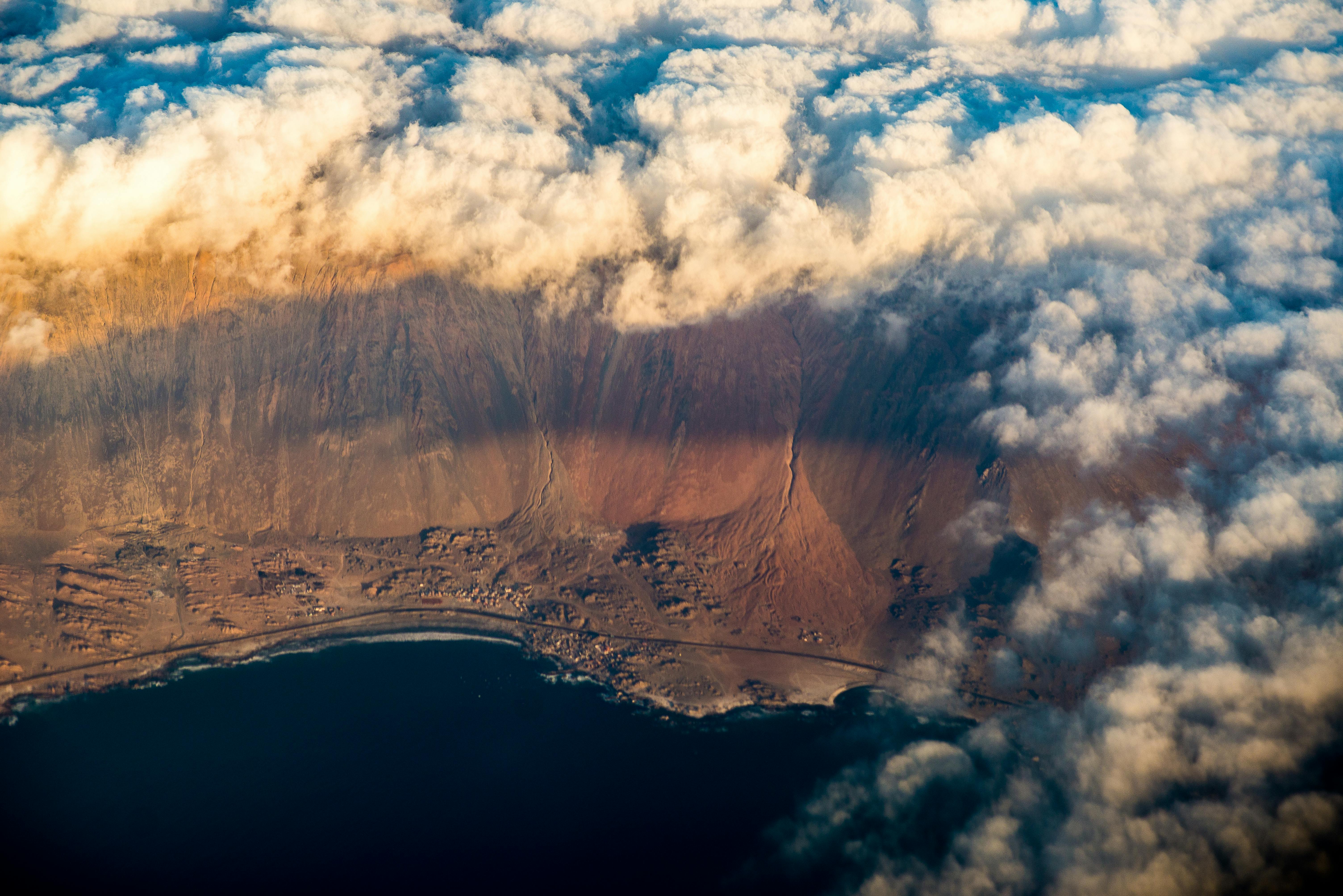 Body of Water Near Mountain Under Clouds · Free Stock Photo