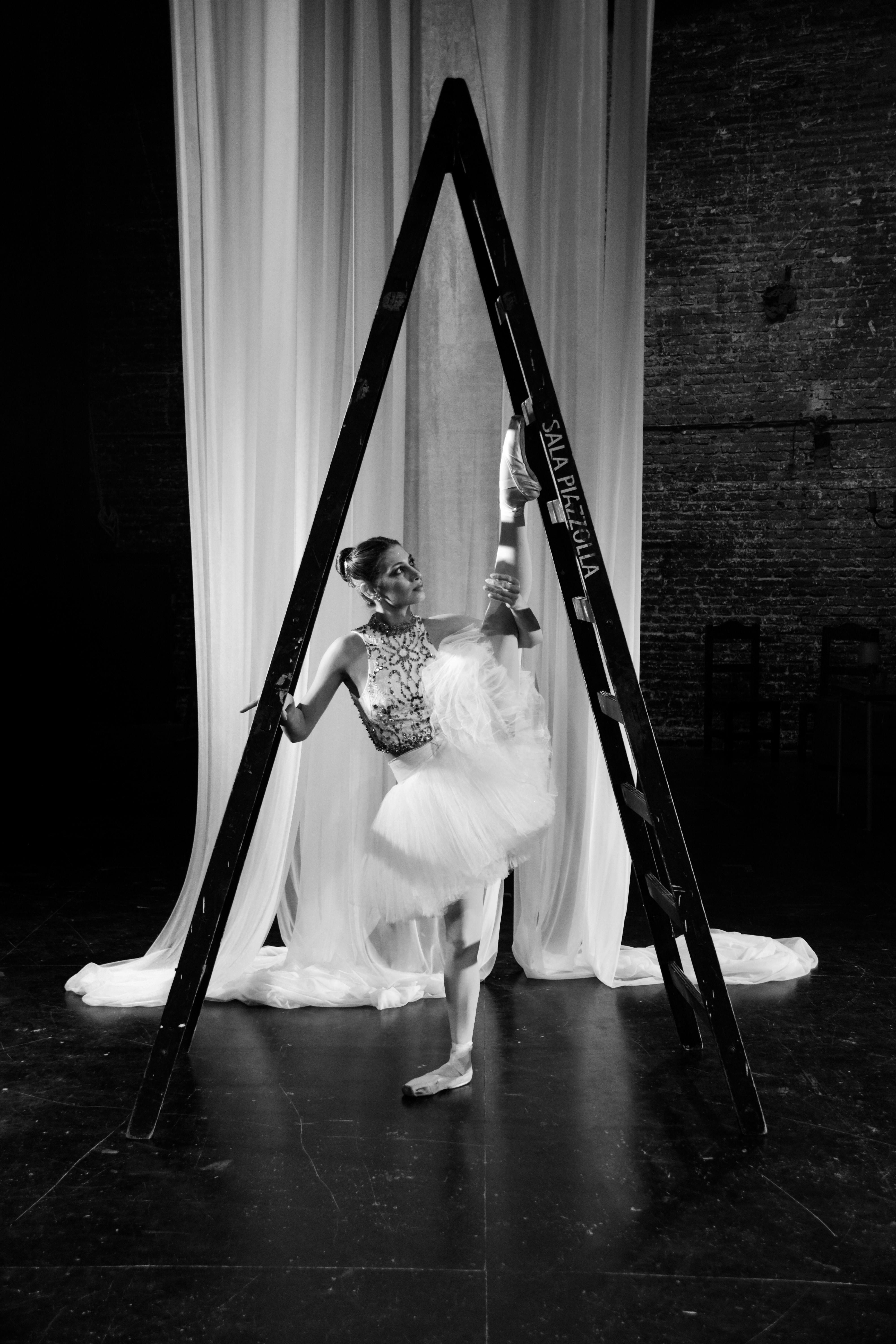 Grayscale Photo of Woman in White Ballet Dress Standing beside a Ladder ...