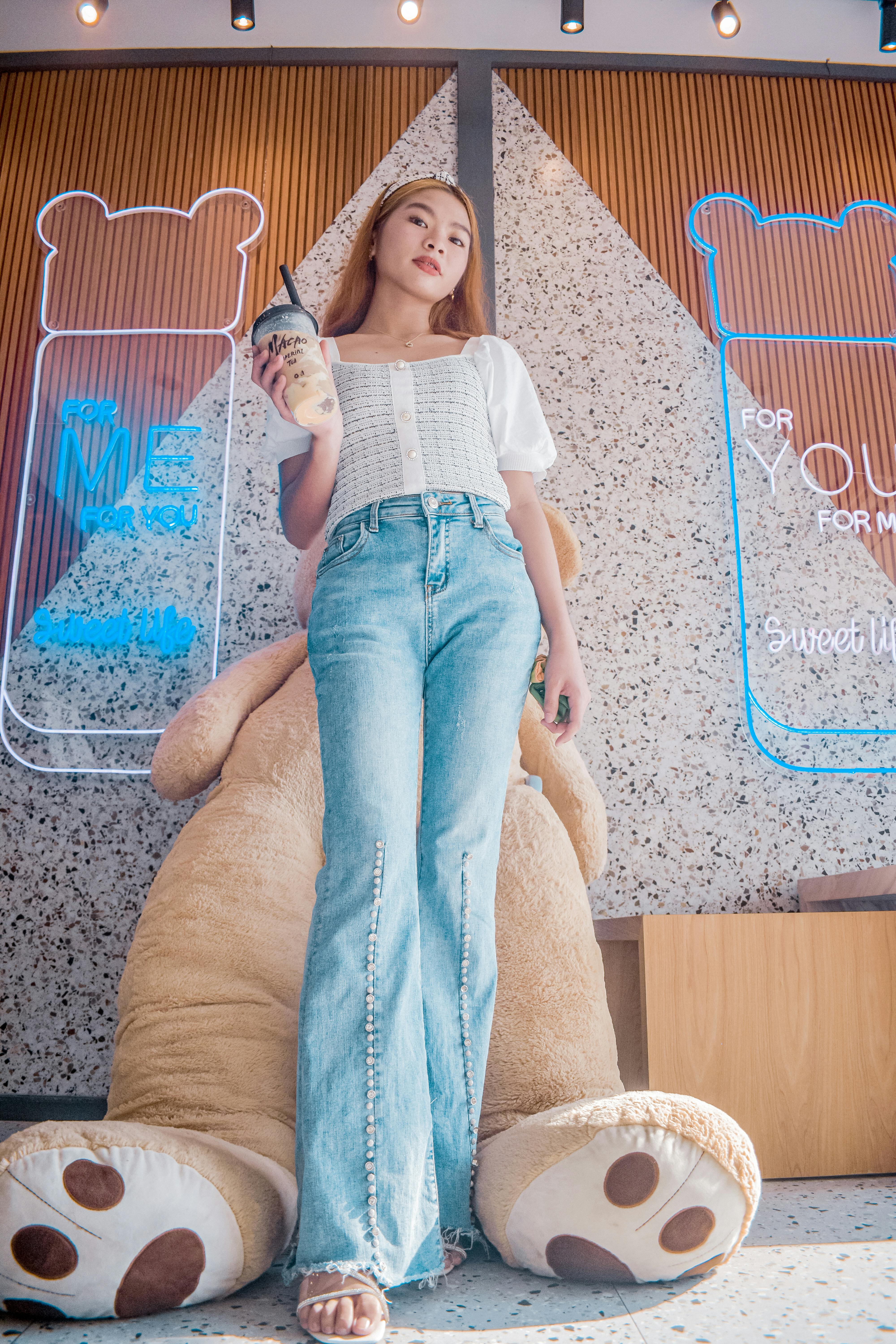 Woman in White Tank Top and Blue Denim Shorts Standing beside Brown ...