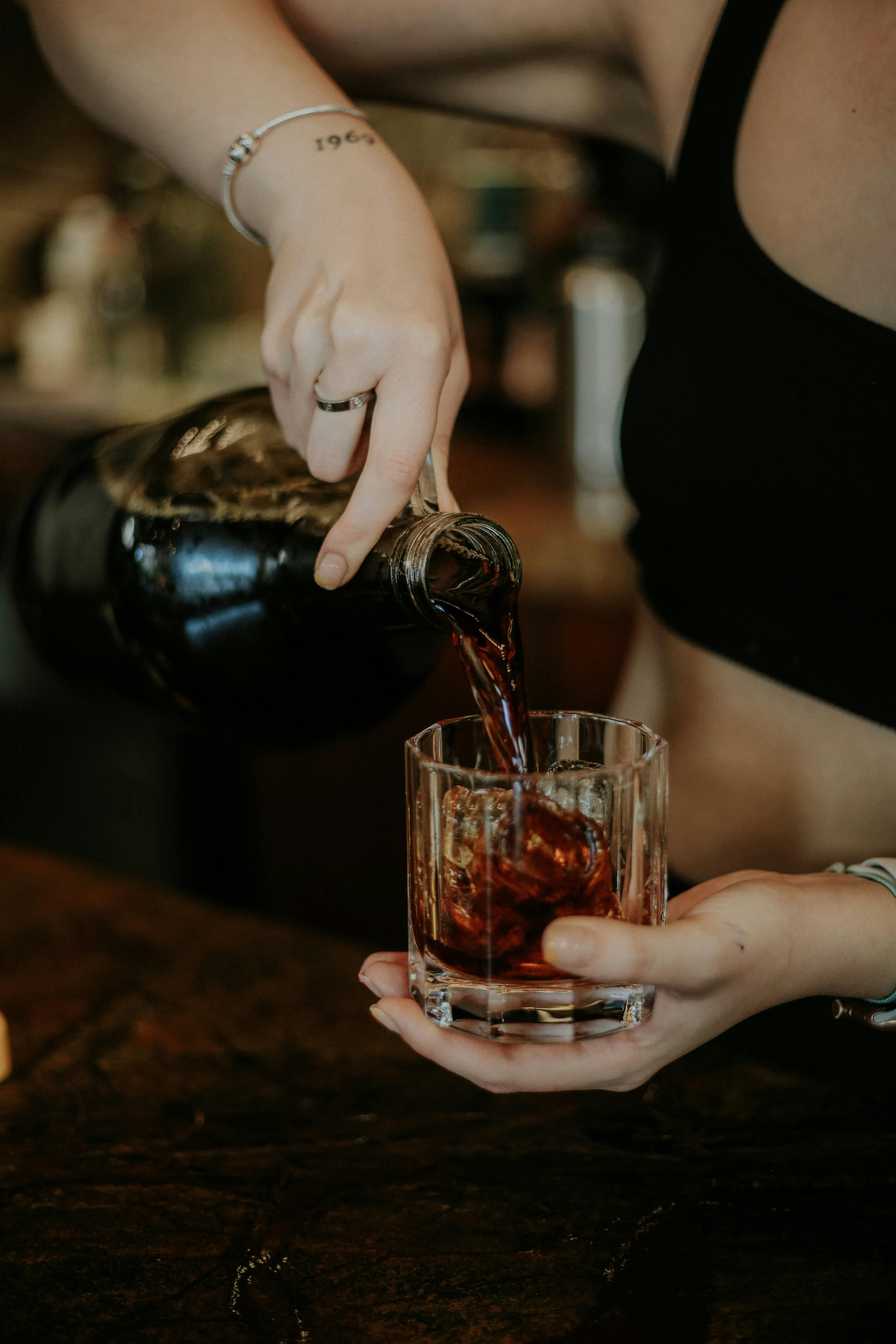 A Person Pouring Drink in a Glass with Ice · Free Stock Photo