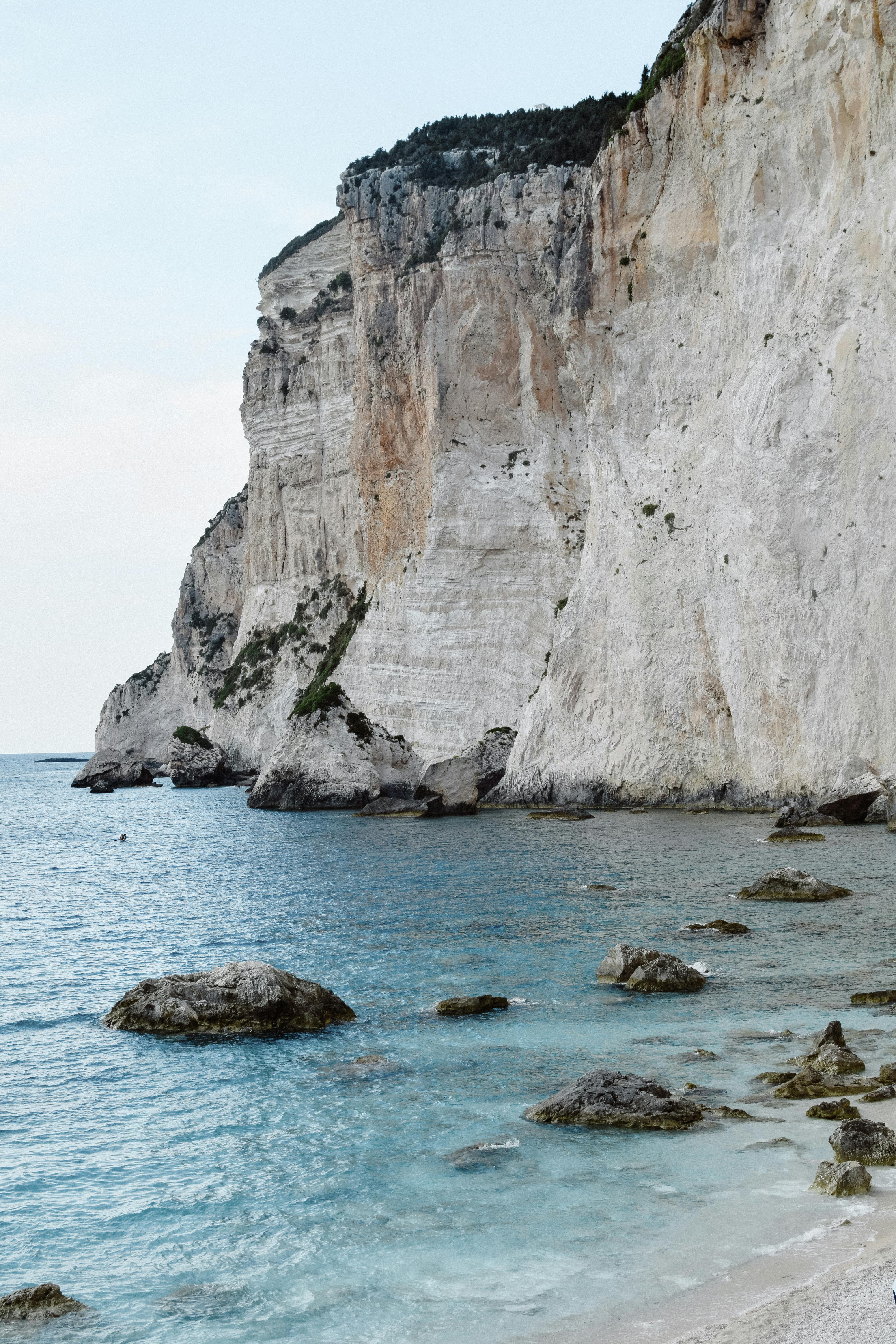 Cliff Towering over Blue Sea · Free Stock Photo