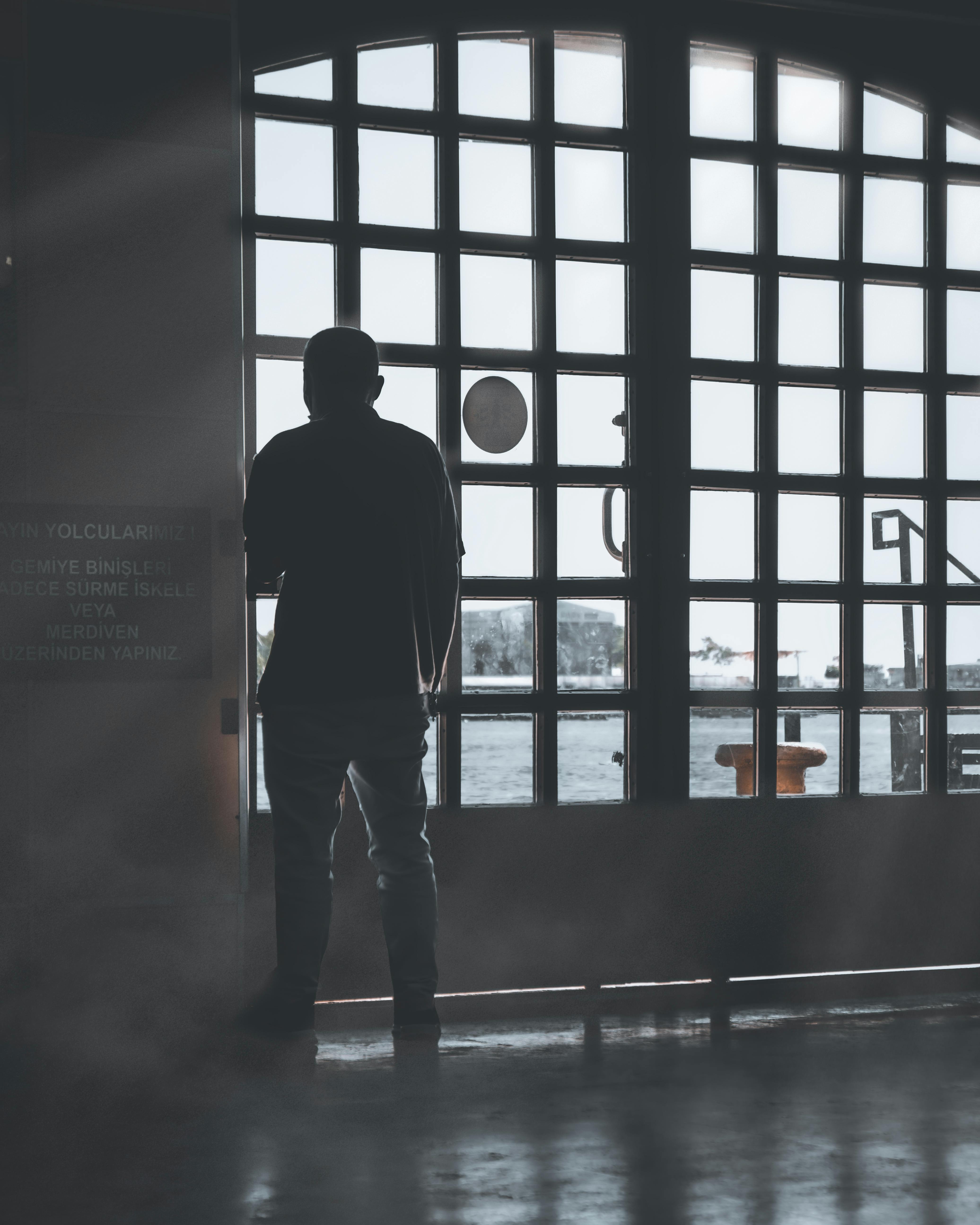 Silhouette of Man Standing beside Window · Free Stock Photo