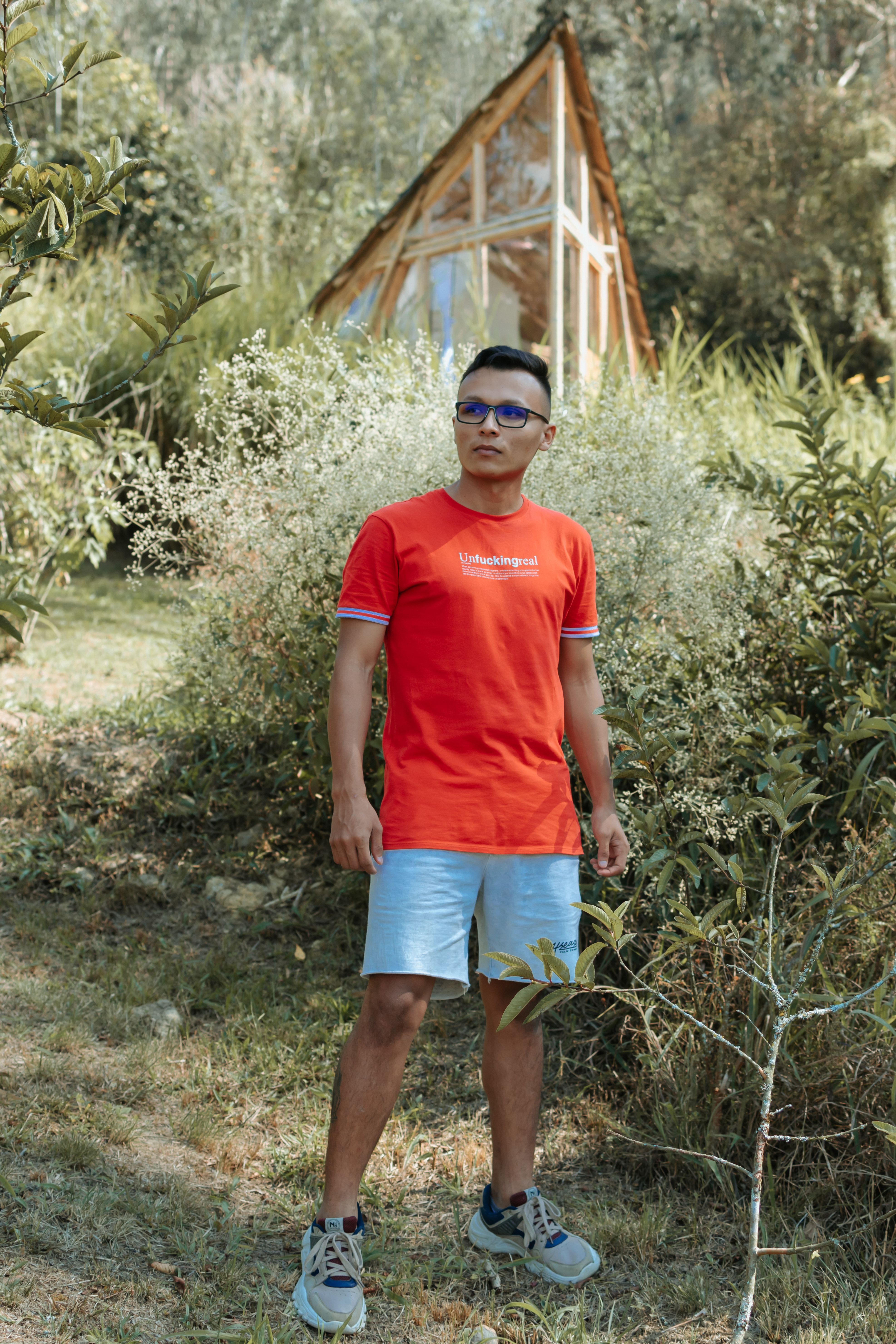 Man Standing Between Trees Wearing T-Shirt and Shorts · Free Stock Photo