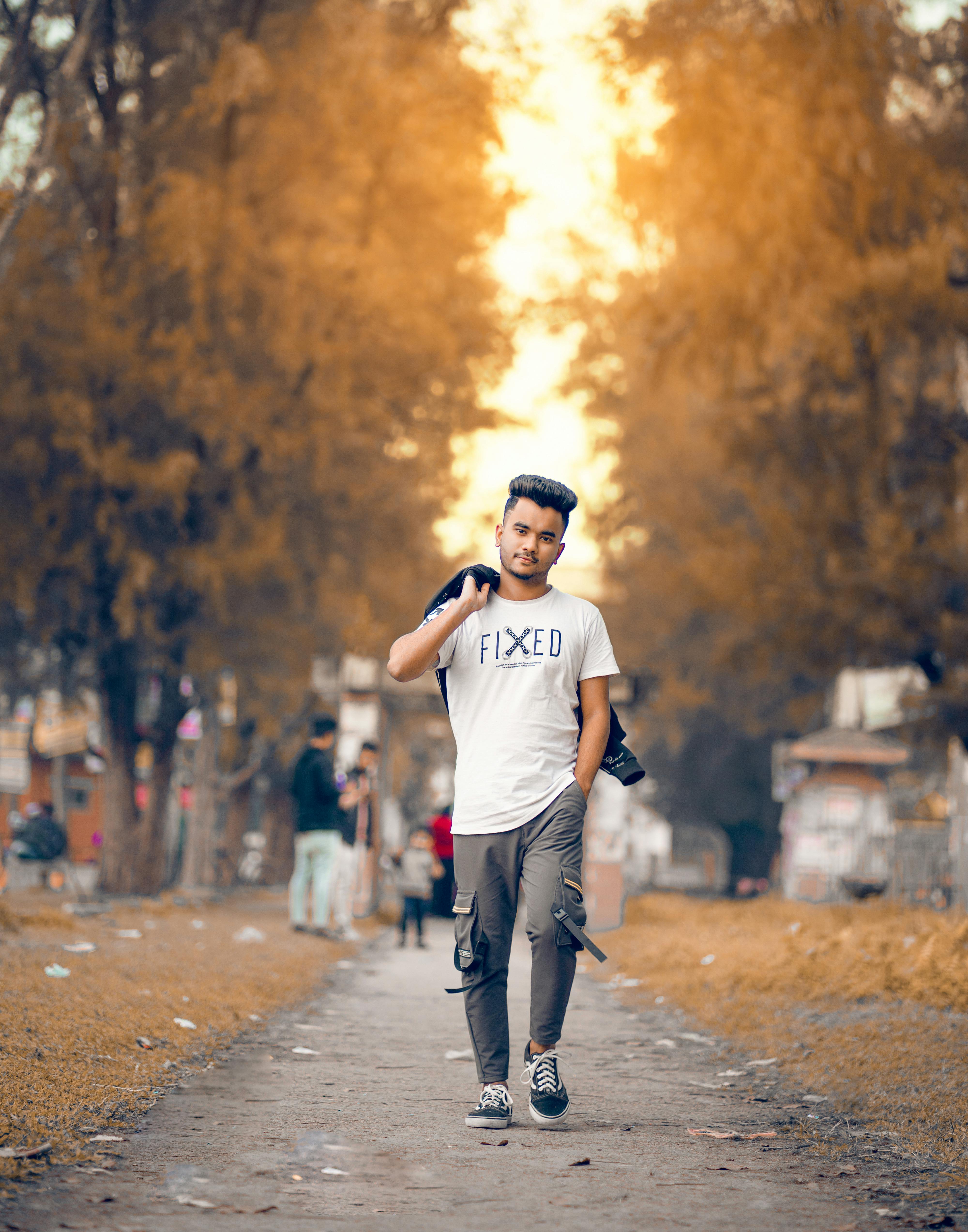 Young Man Walking down the Pedestrian Road in a Park · Free Stock Photo