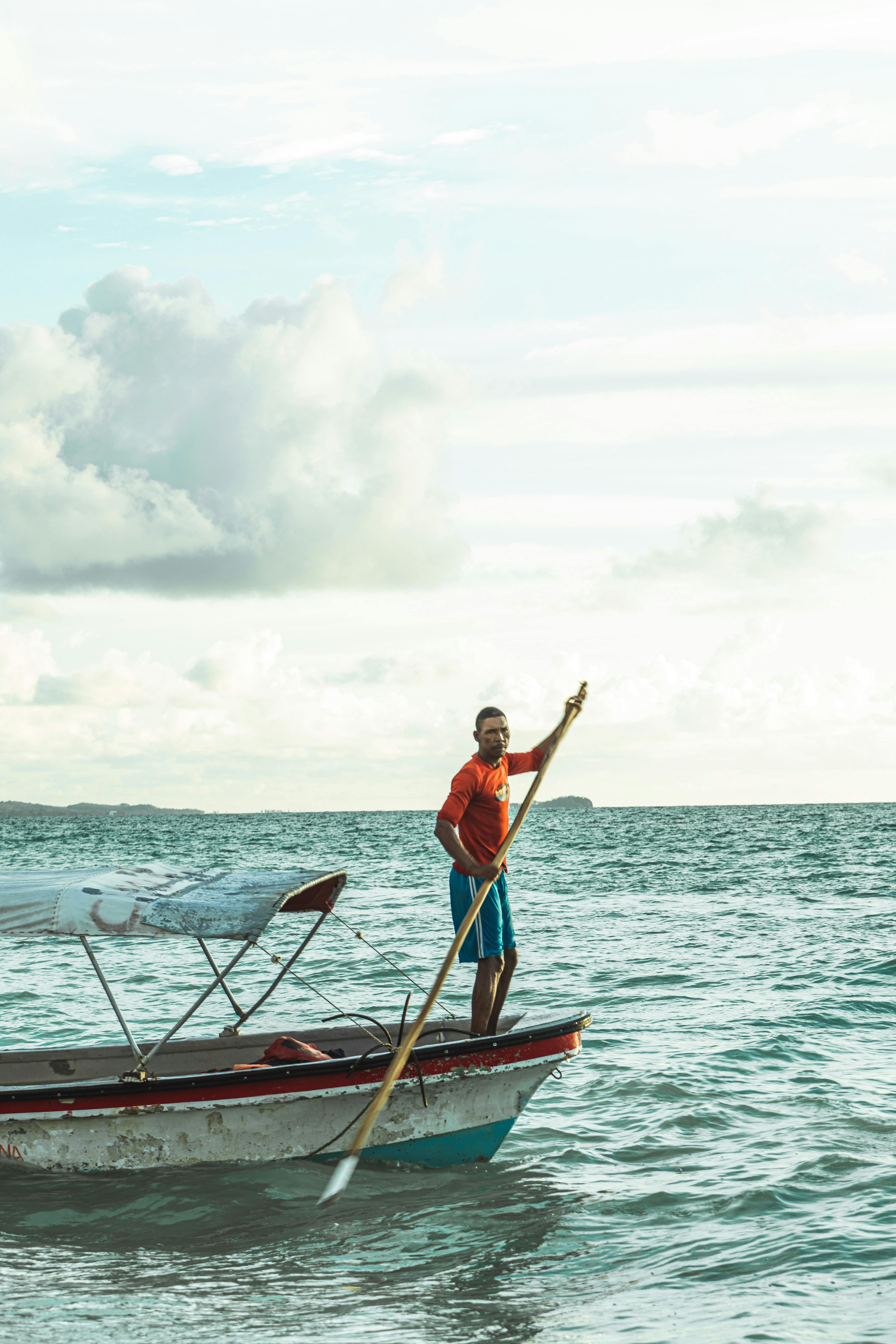 Man in Red Shirt and Blue Shorts Riding on Boat · Free Stock Photo