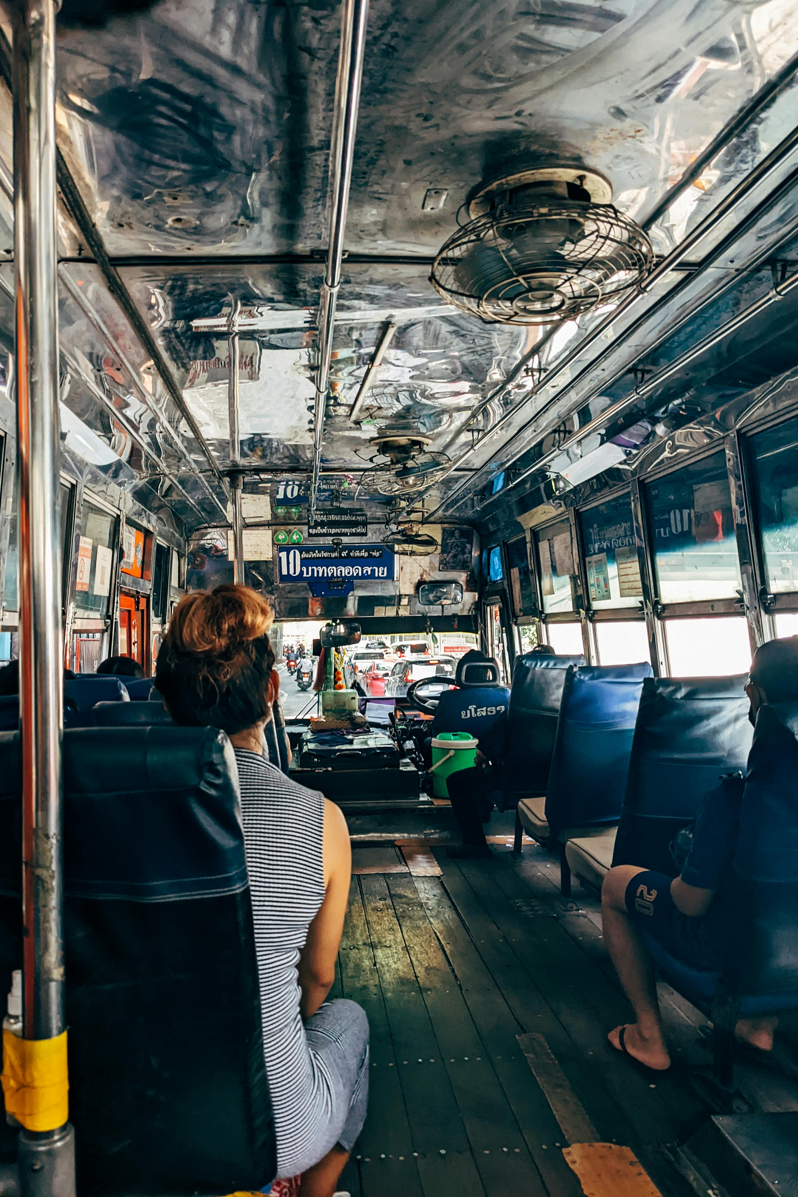 Woman Sitting on Wall behind Bus · Free Stock Photo