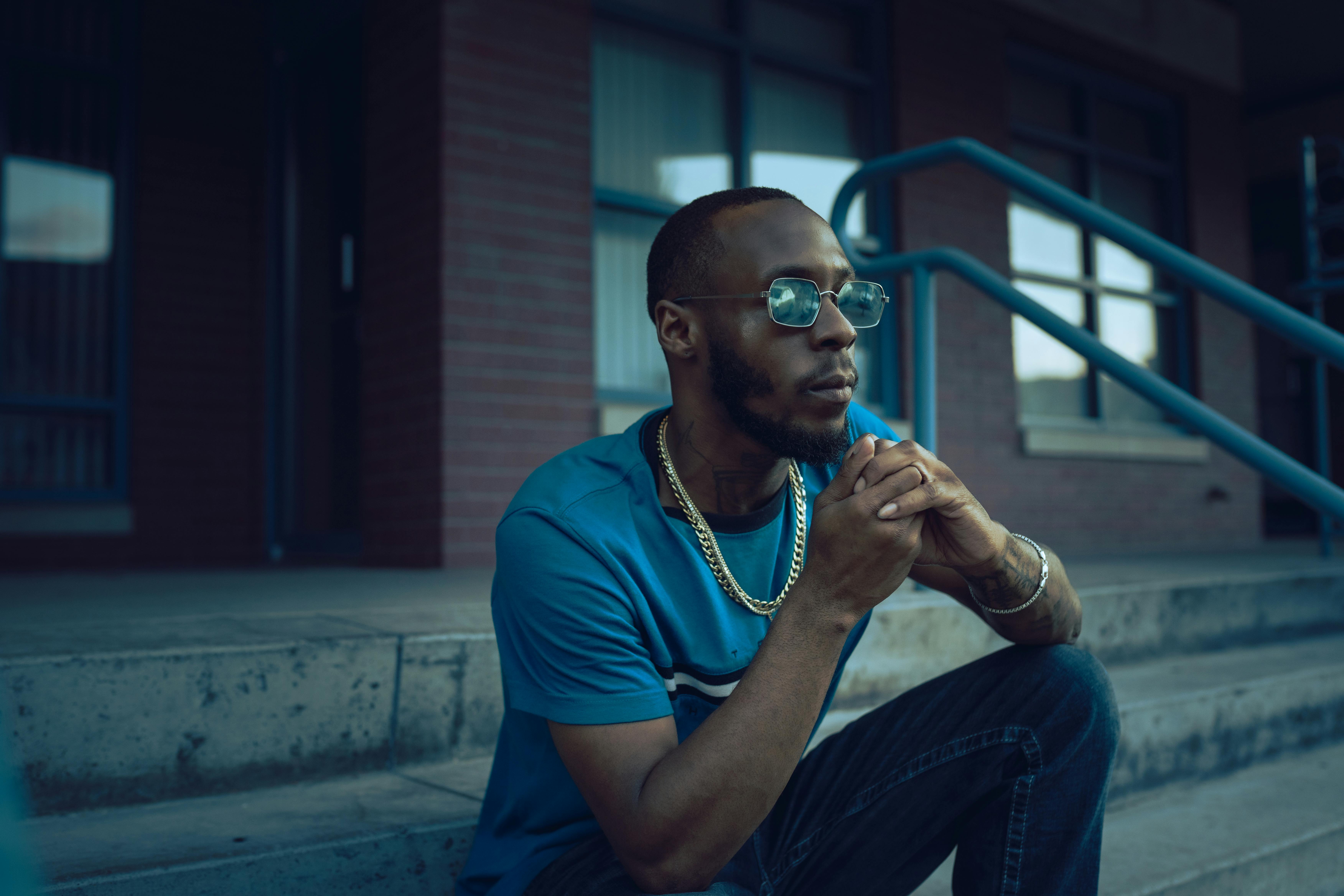 Young Man Sitting on Stairs in City Wearing Sunglasses · Free Stock Photo