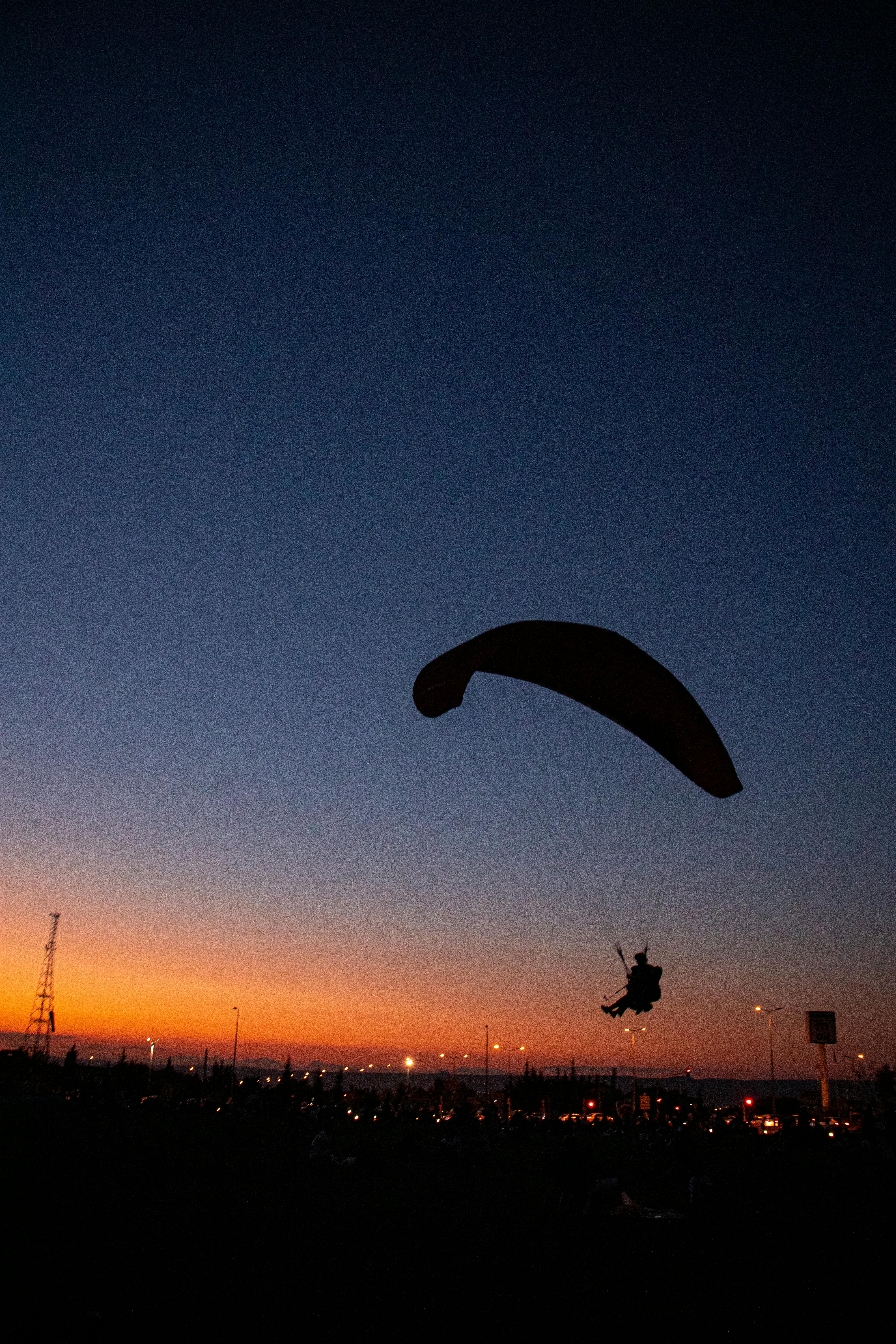 Silhouette of a Man Parachuting at Sunset · Free Stock Photo