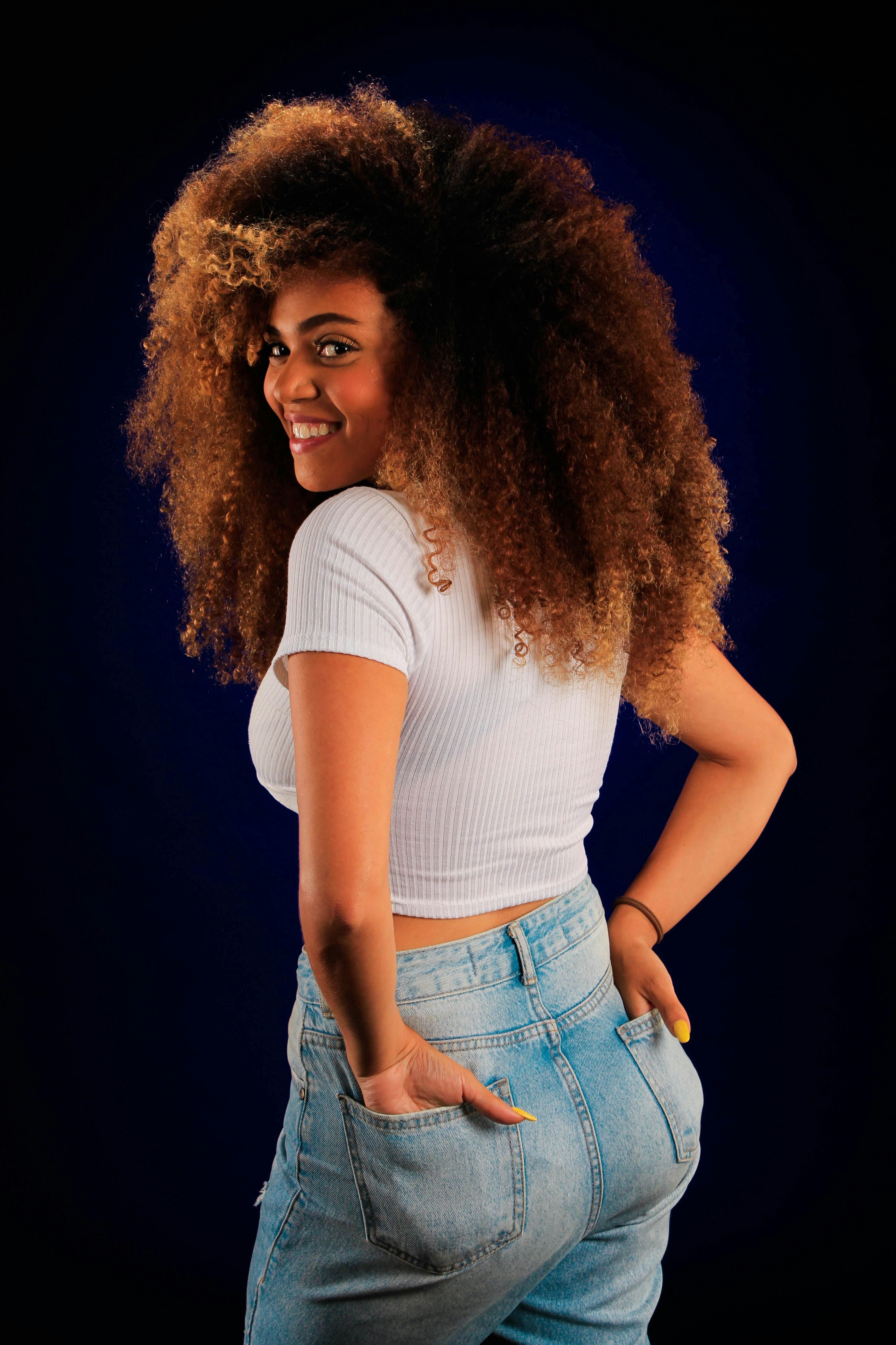 A Woman Wearing White Crop Top and Denim Jeans Looking Over Shoulder ...