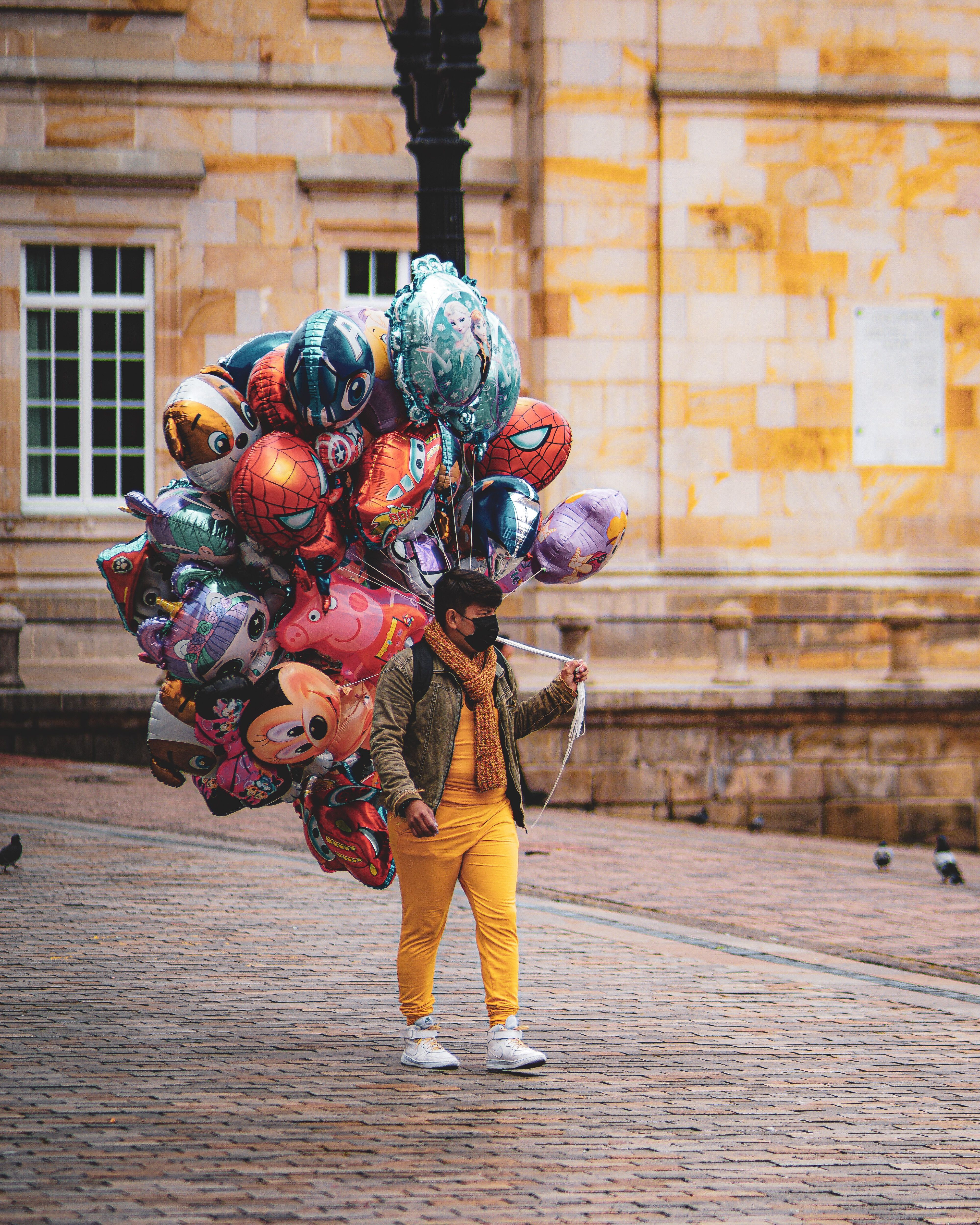 A Man Holding Balloons While Walking · Free Stock Photo