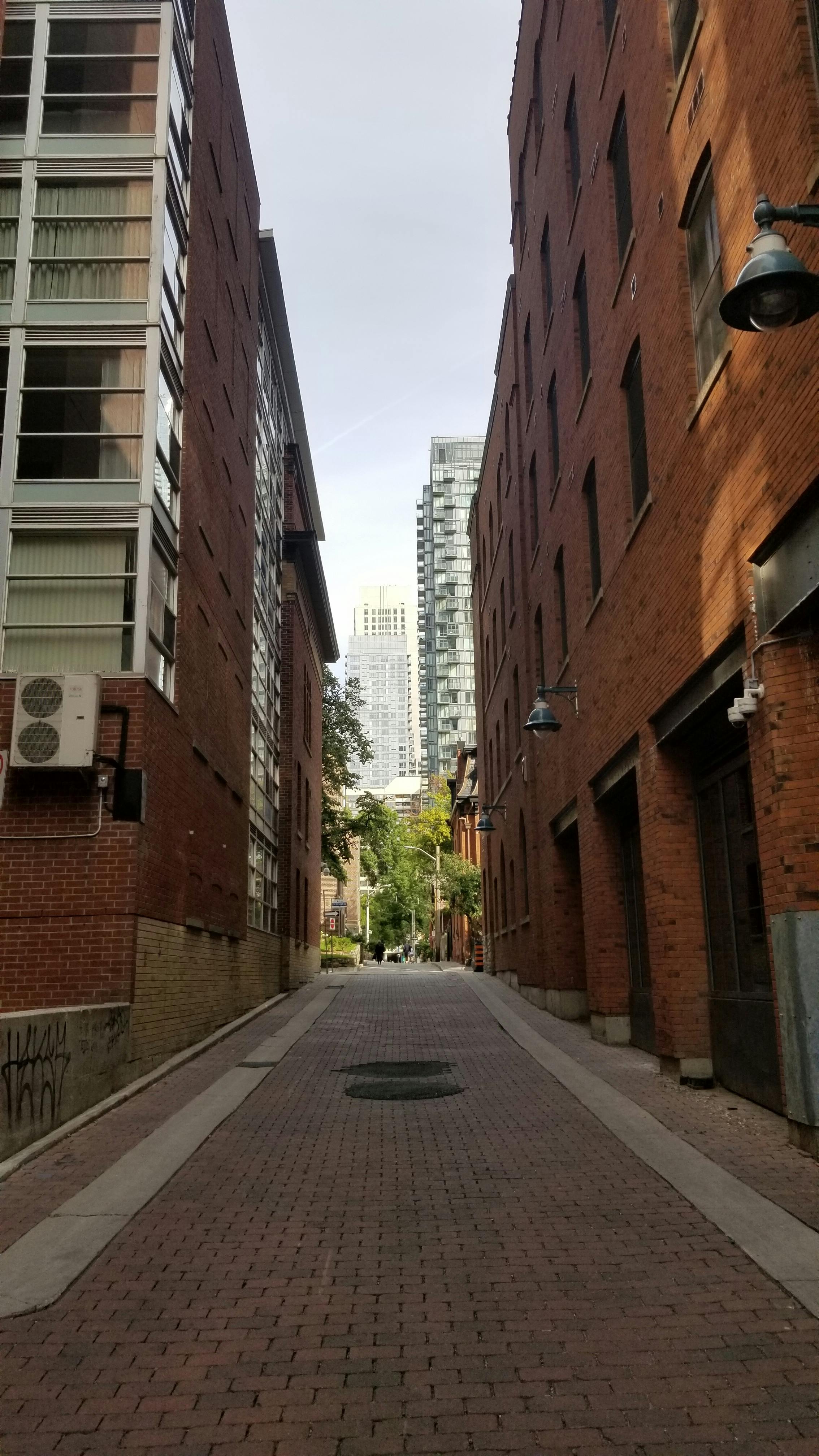 Stone Paved Alley in between Brown Concrete Buildings · Free Stock Photo