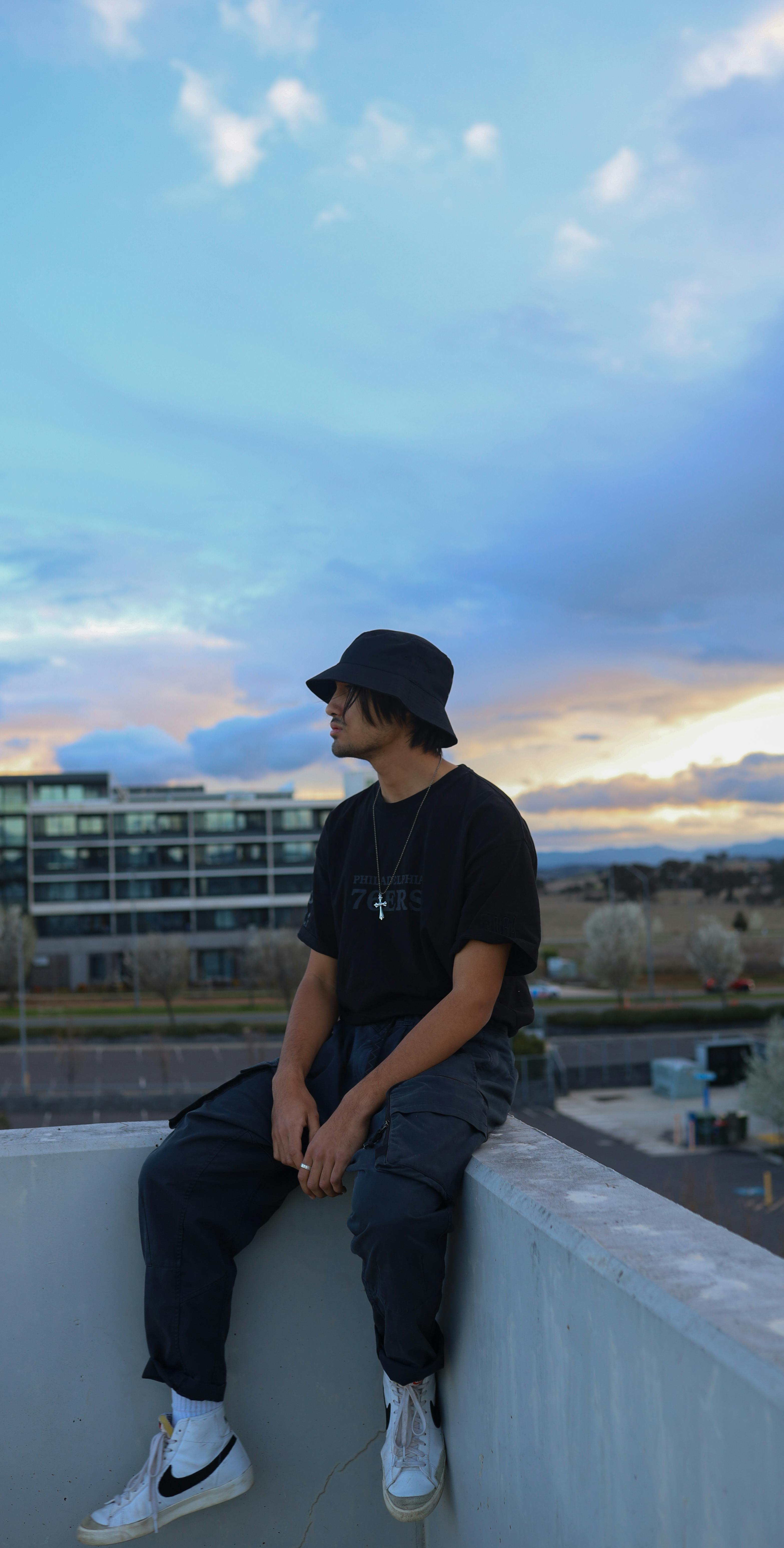 A Man Sitting on Ledge of a Rooftop · Free Stock Photo