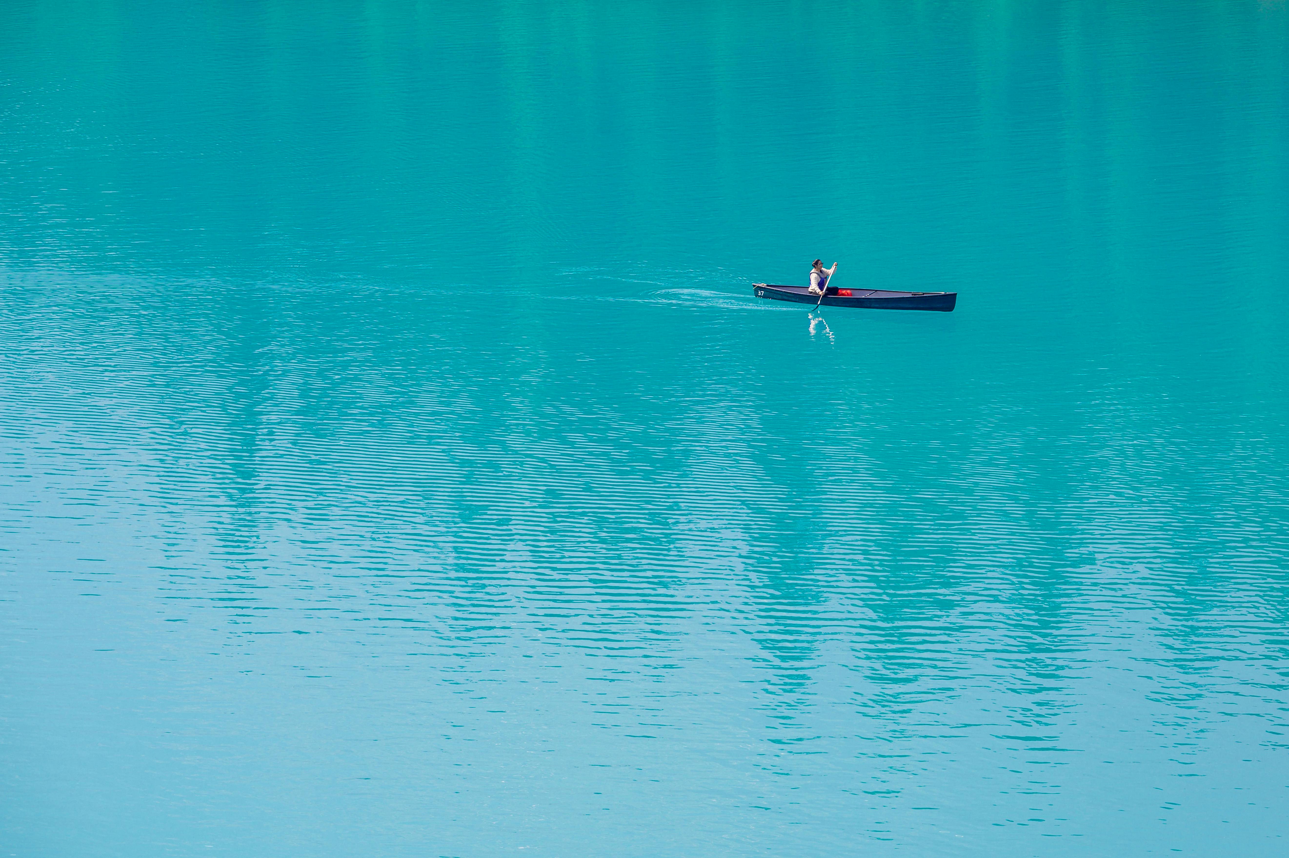 Person Riding on Canoe Rowing on Turquoise Sea · Free Stock Photo