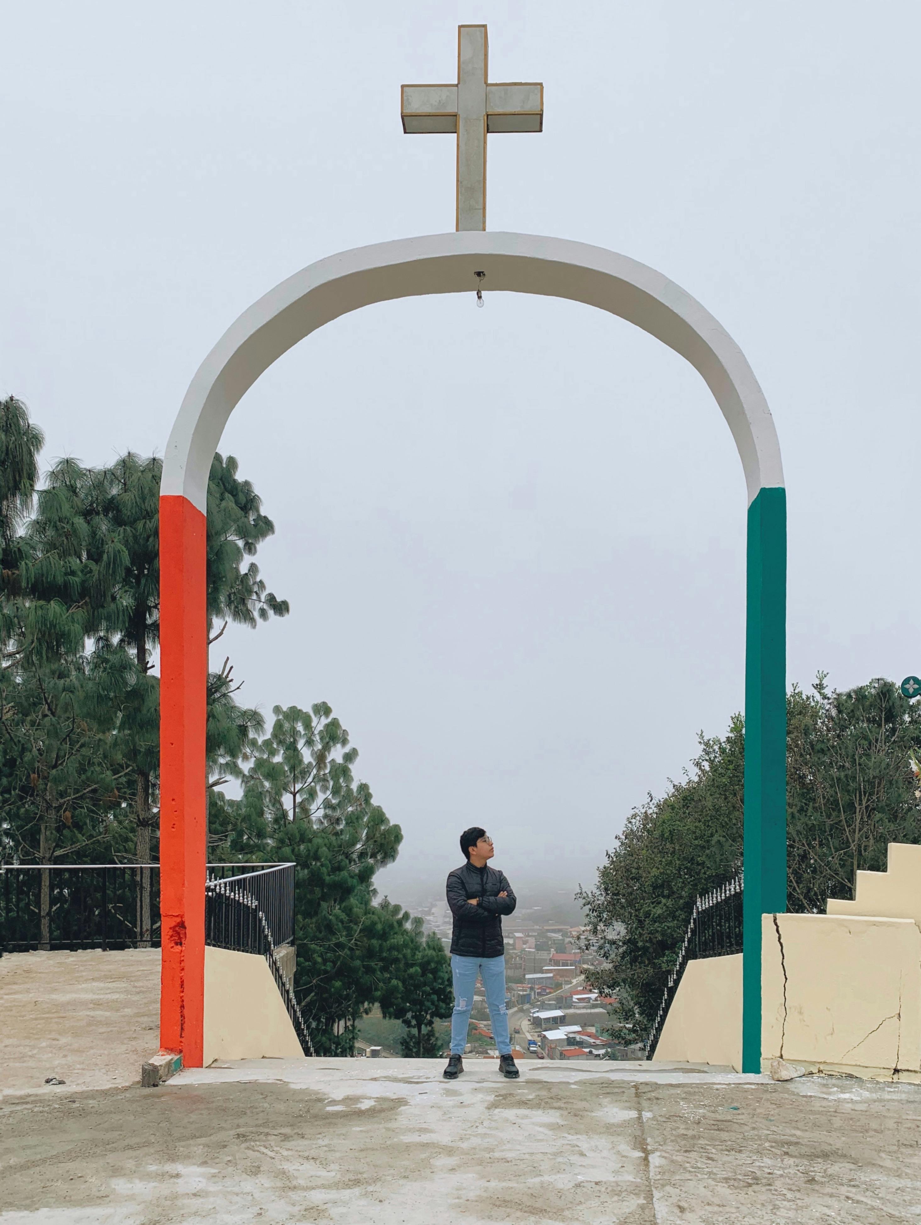 Man Posing under Gate with Cross · Free Stock Photo