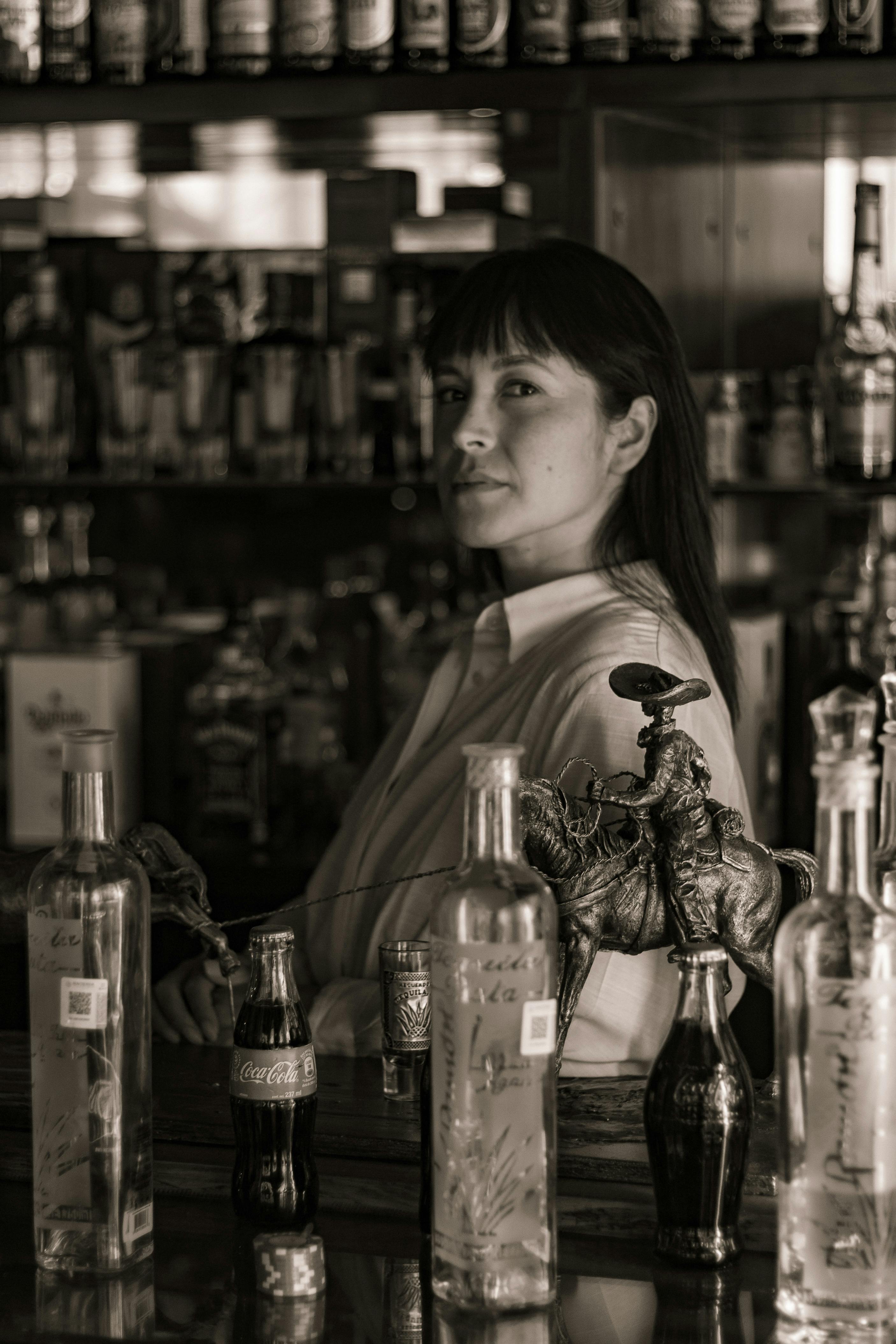 Grayscale Photo of a Woman Standing Behind Bar Counter · Free Stock Photo