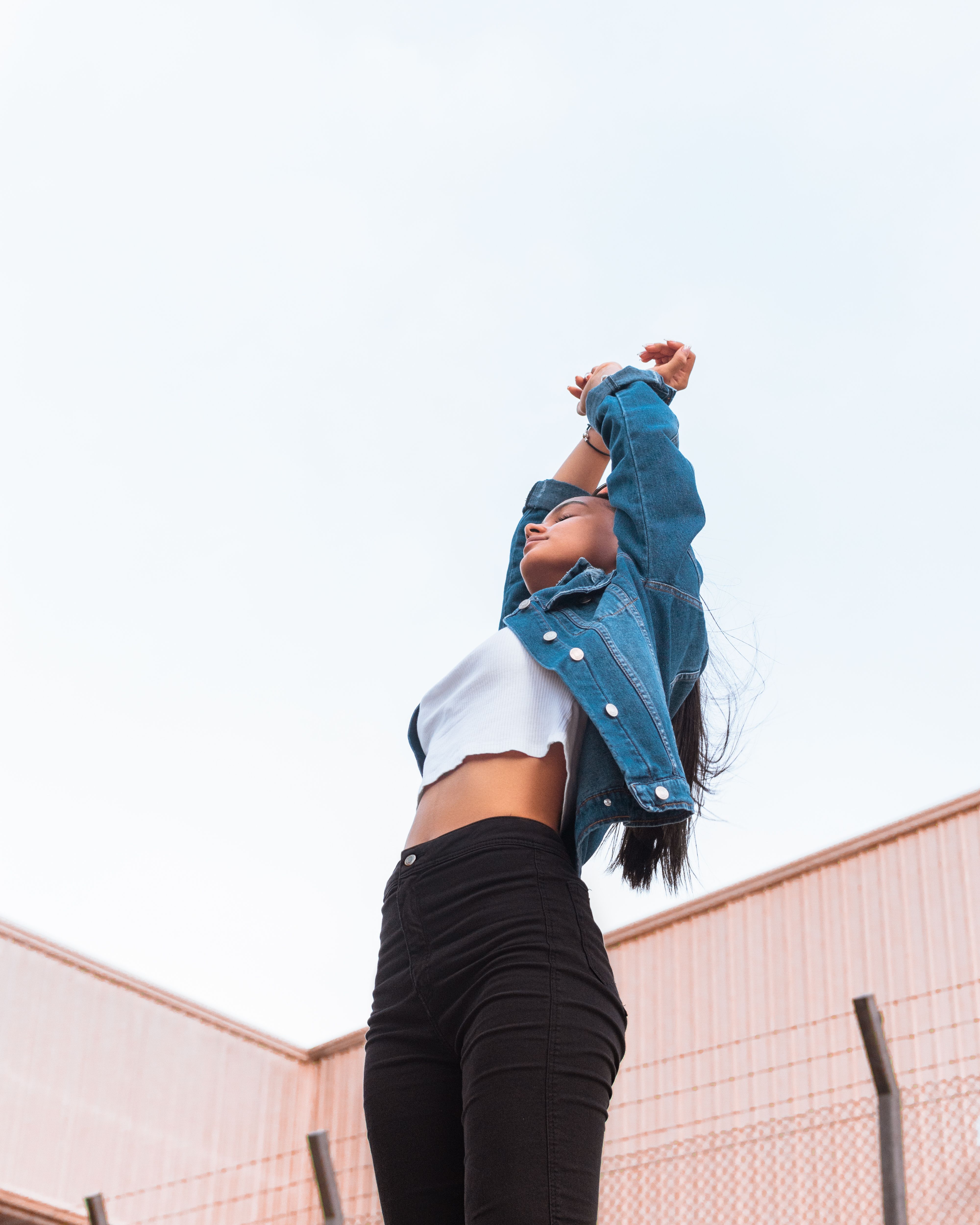 Woman in Jean Jacket Standing with Arms Raised · Free Stock Photo