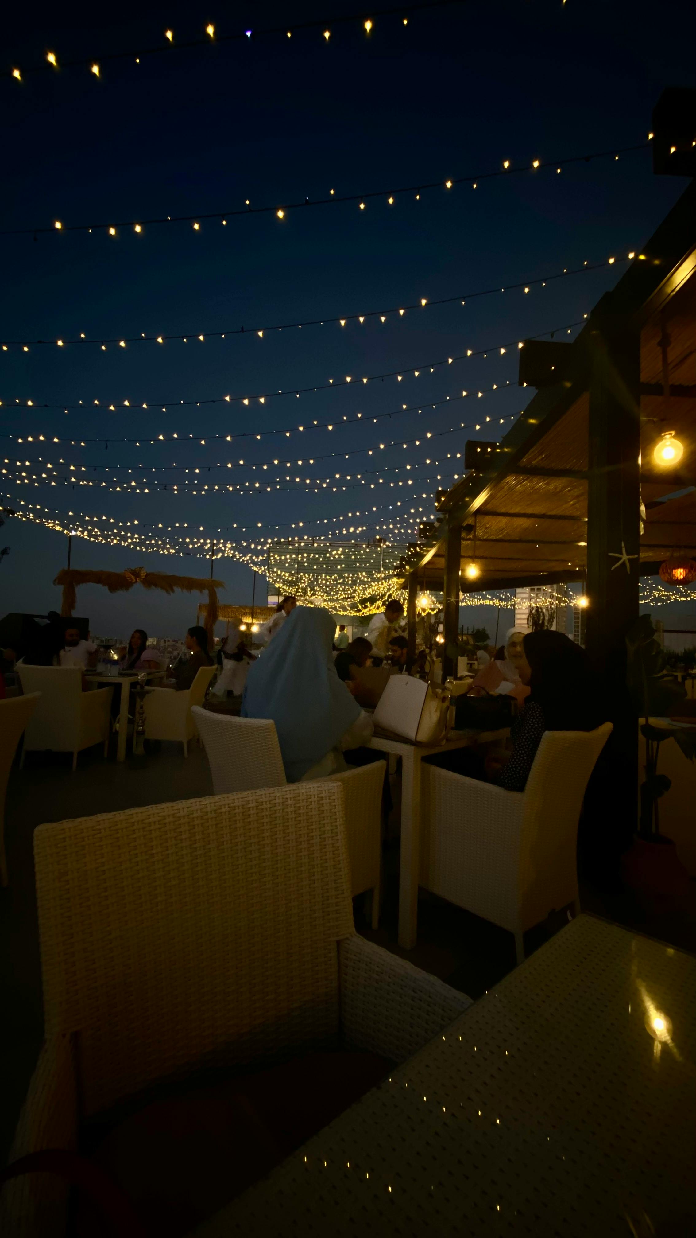 Lights over People Sitting on Chairs at Night · Free Stock Photo