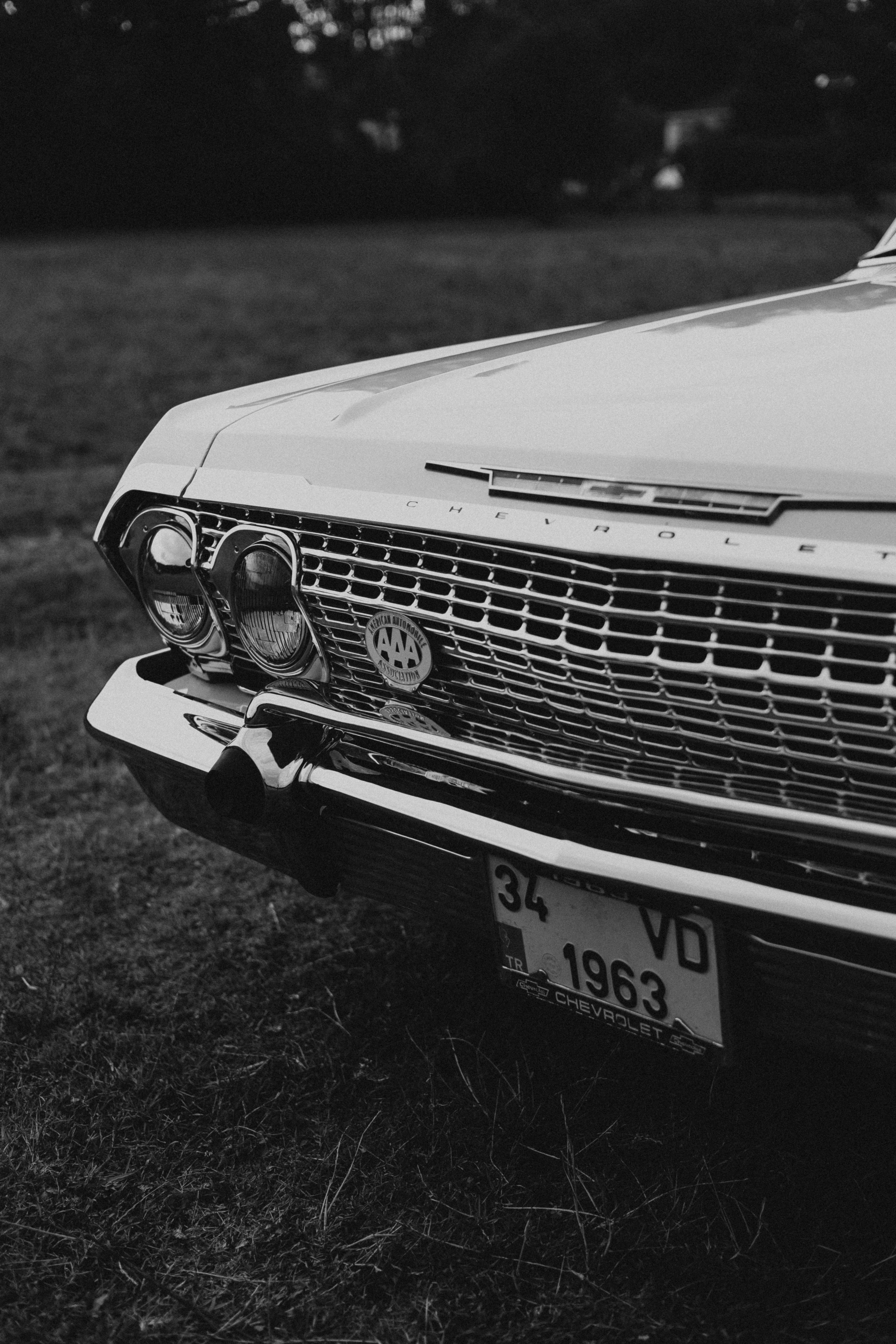 Grayscale Photo of a Classic Car Parked on Grass · Free Stock Photo