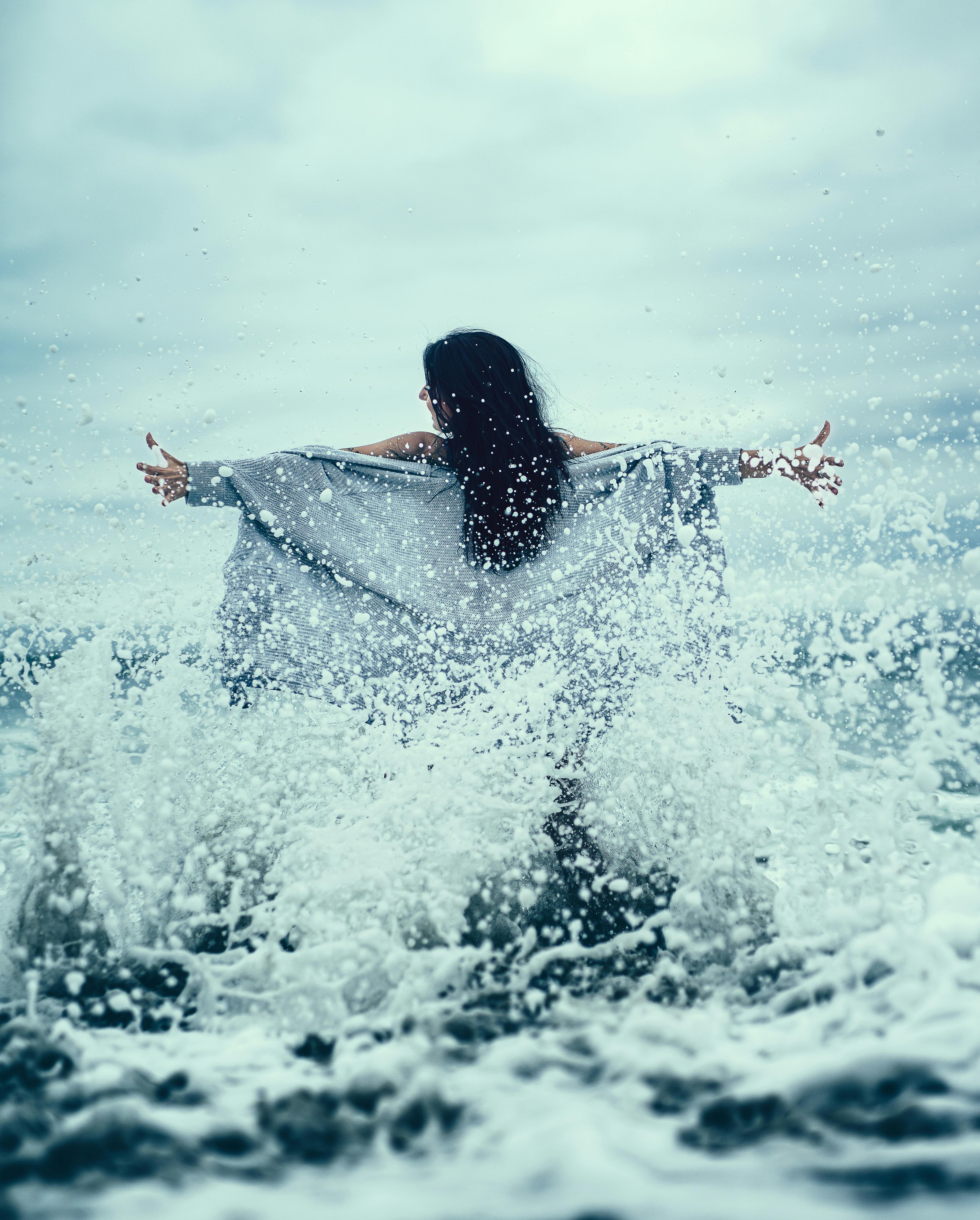 Back View of a Woman Standing in Water with Her Arms Spread Around ...