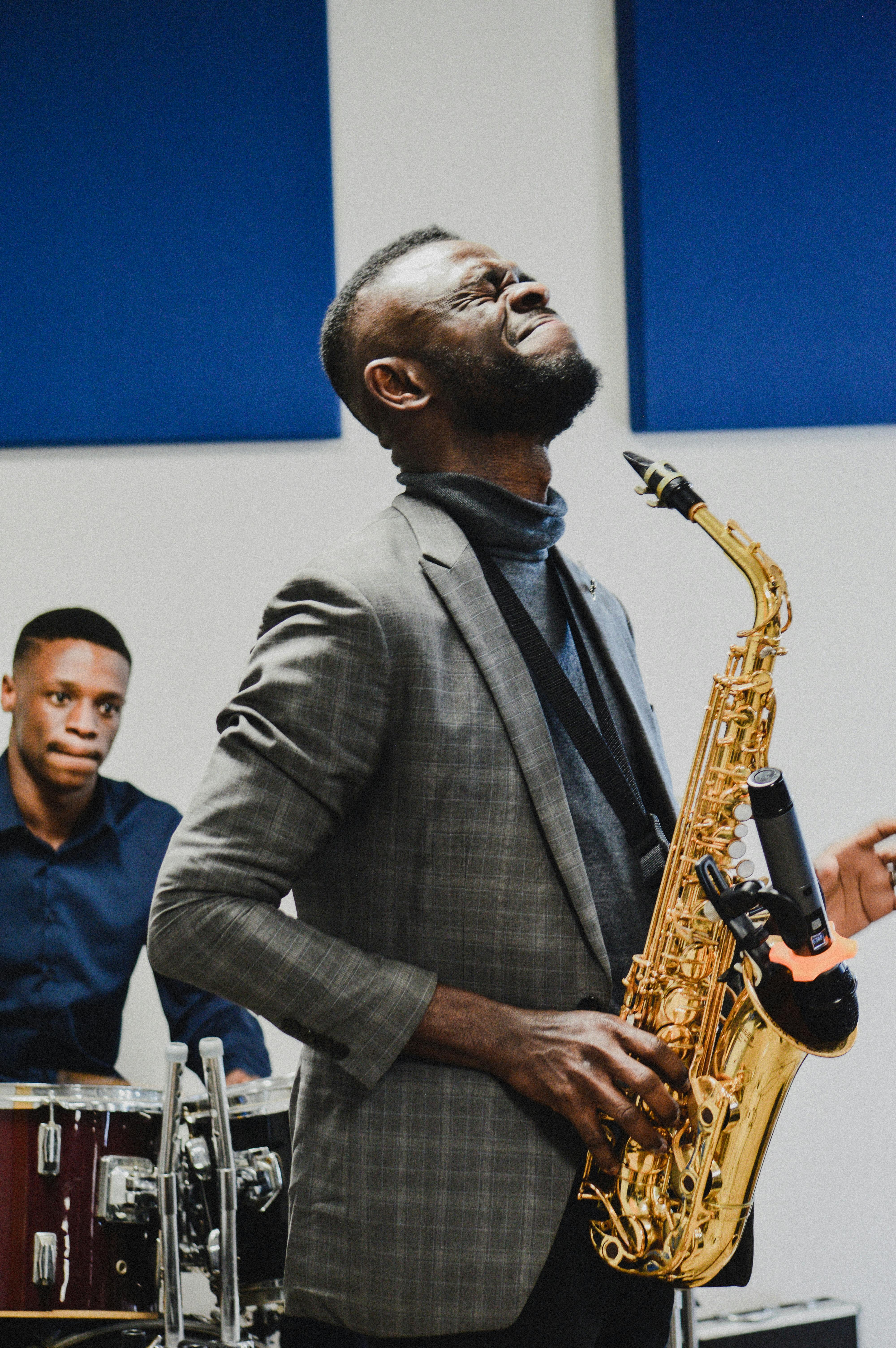 Man Sitting on White Couch Holding a Saxophone · Free Stock Photo